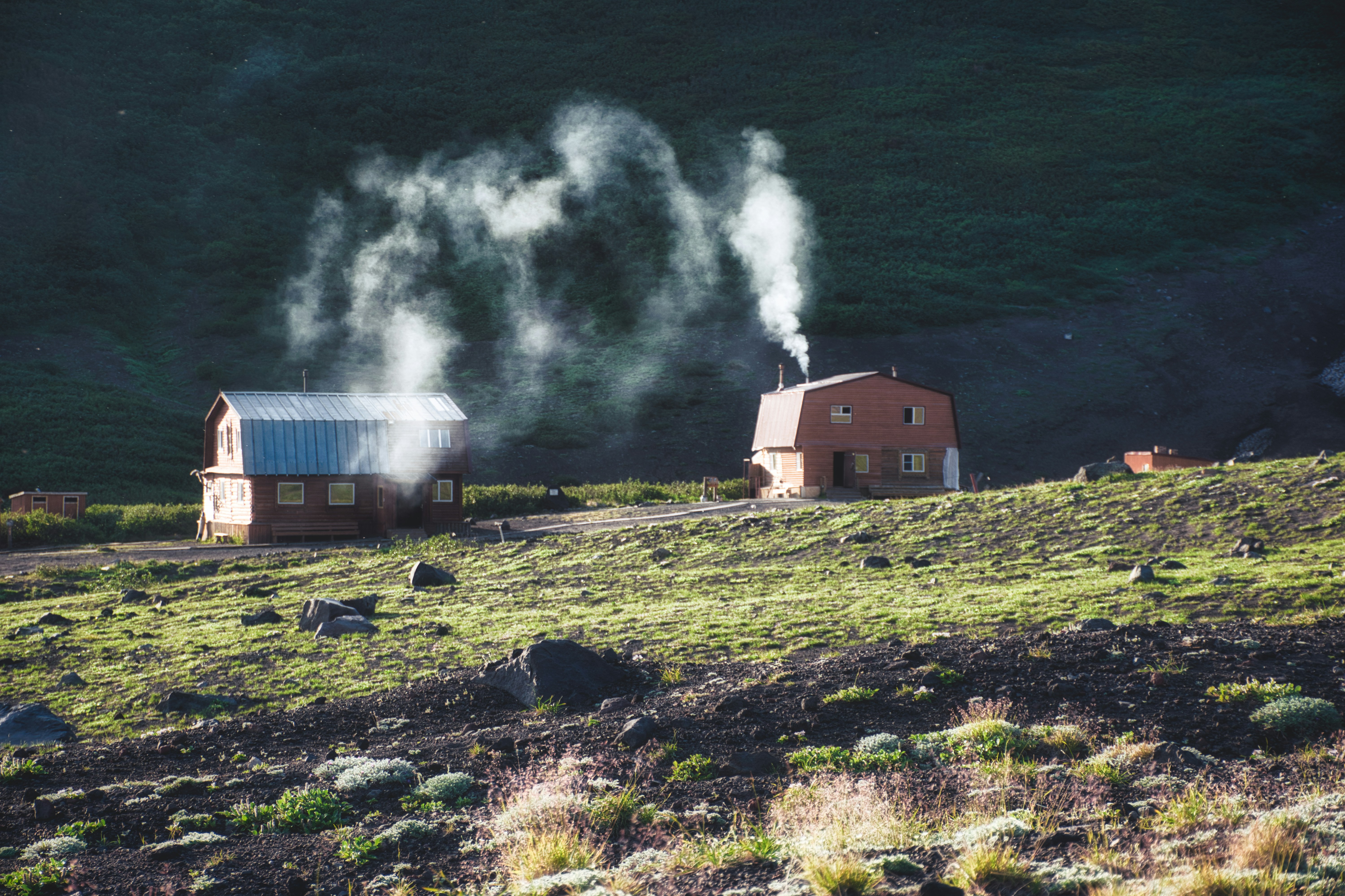 Smoke Rising from Red Roofed Outbuildings on Wind-Swept Field