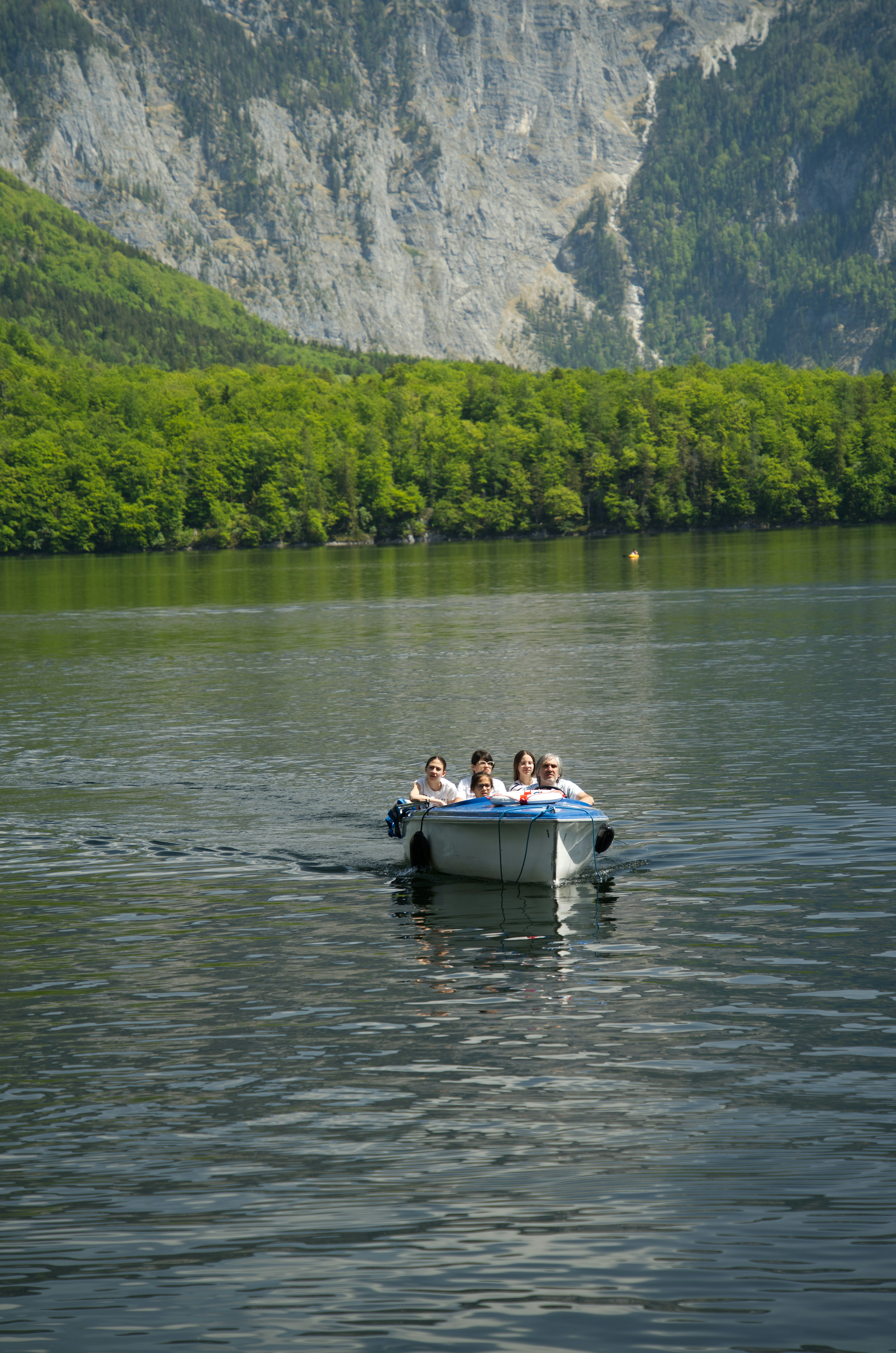 Boat of Friends Drifting Beneath a Verdant Cliff