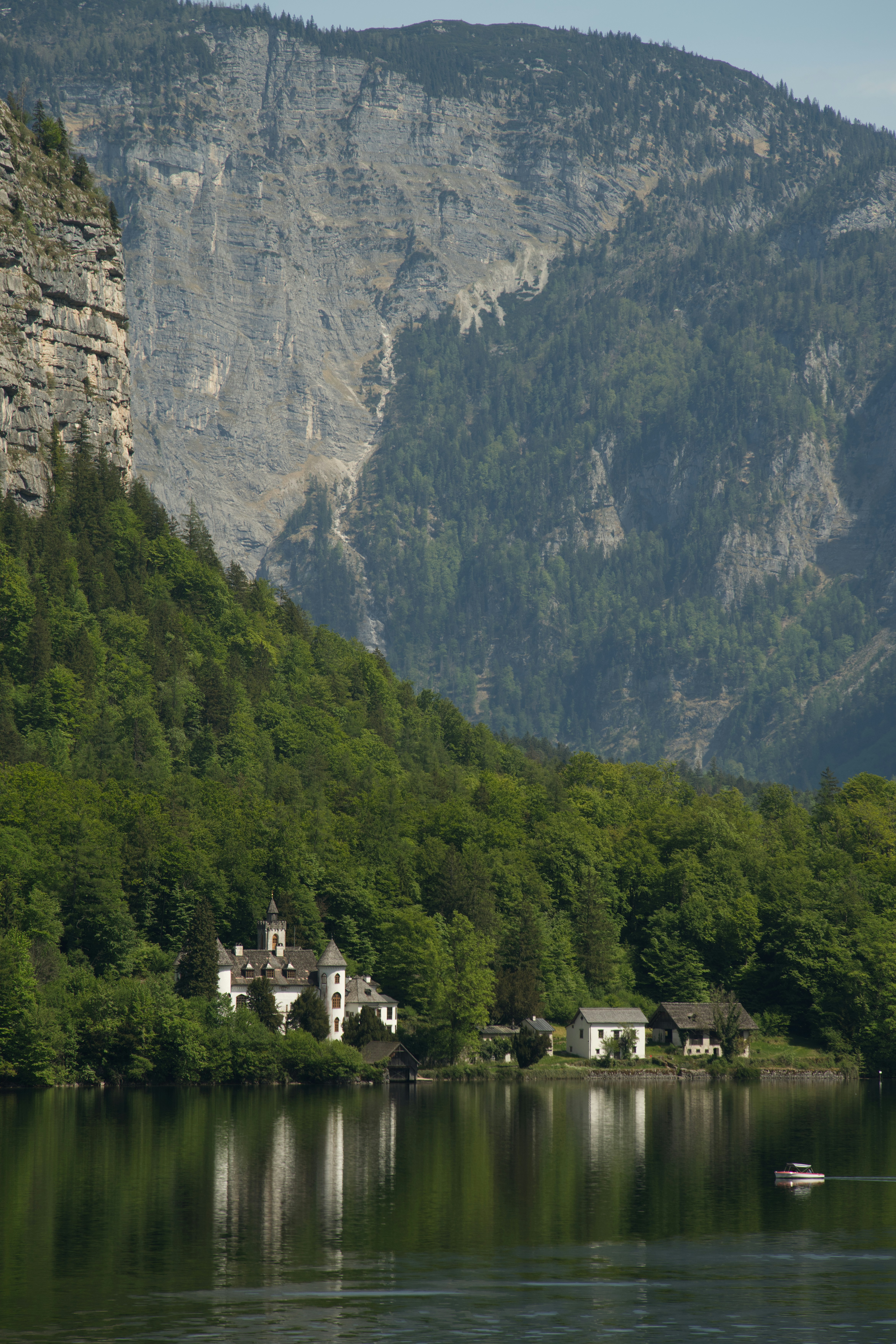 Secluded lakeside chapel at the base of forested cliffs