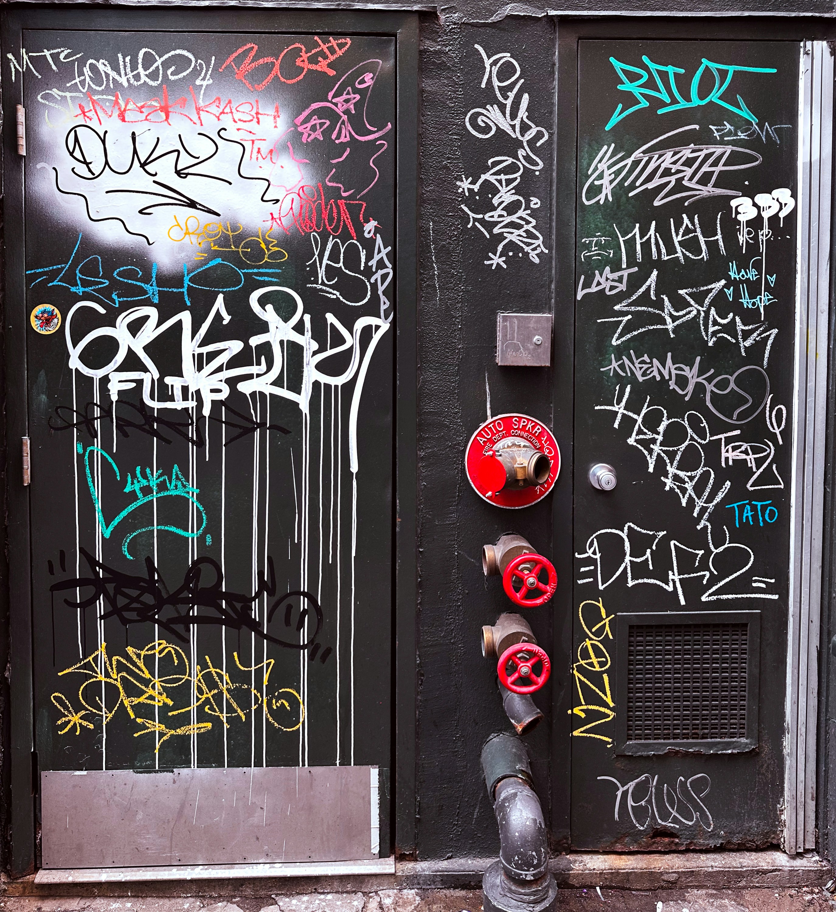 Graffitied Doorway with Red Valve Caps as Silent Sentinels