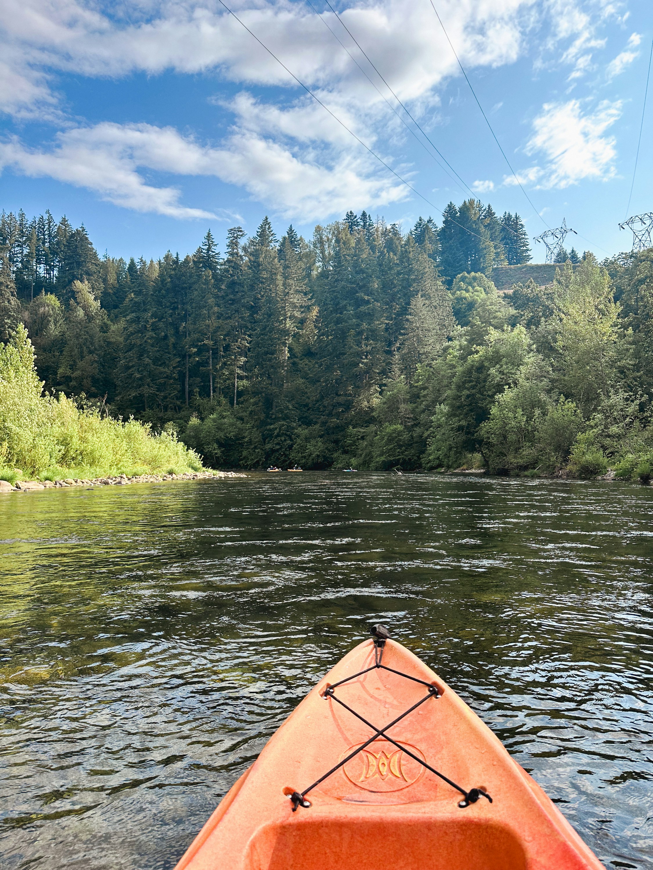 Orange Kayak Leads a River Corridor Toward a Forested Bend
