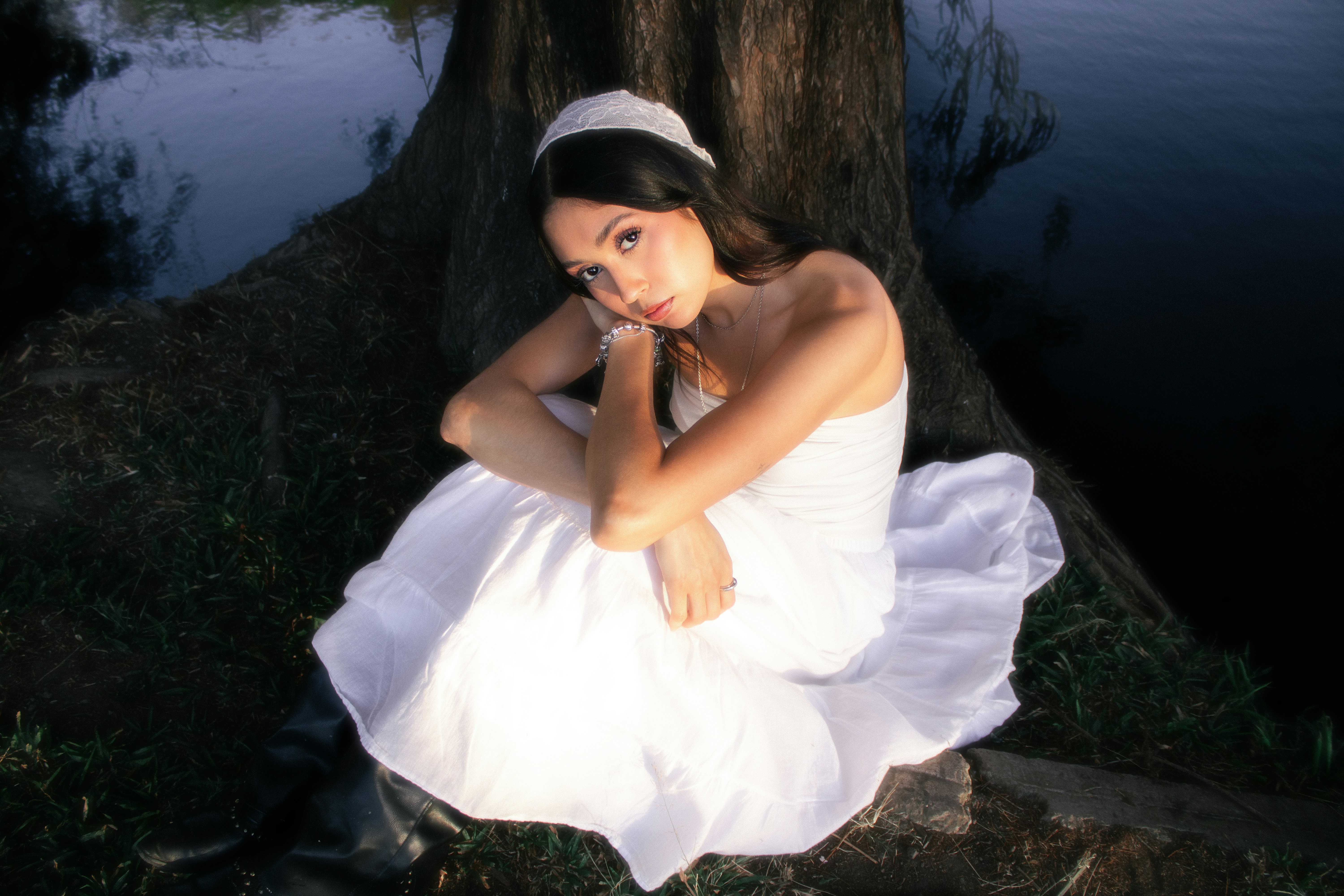 White-dress muse by the water under a shaded tree