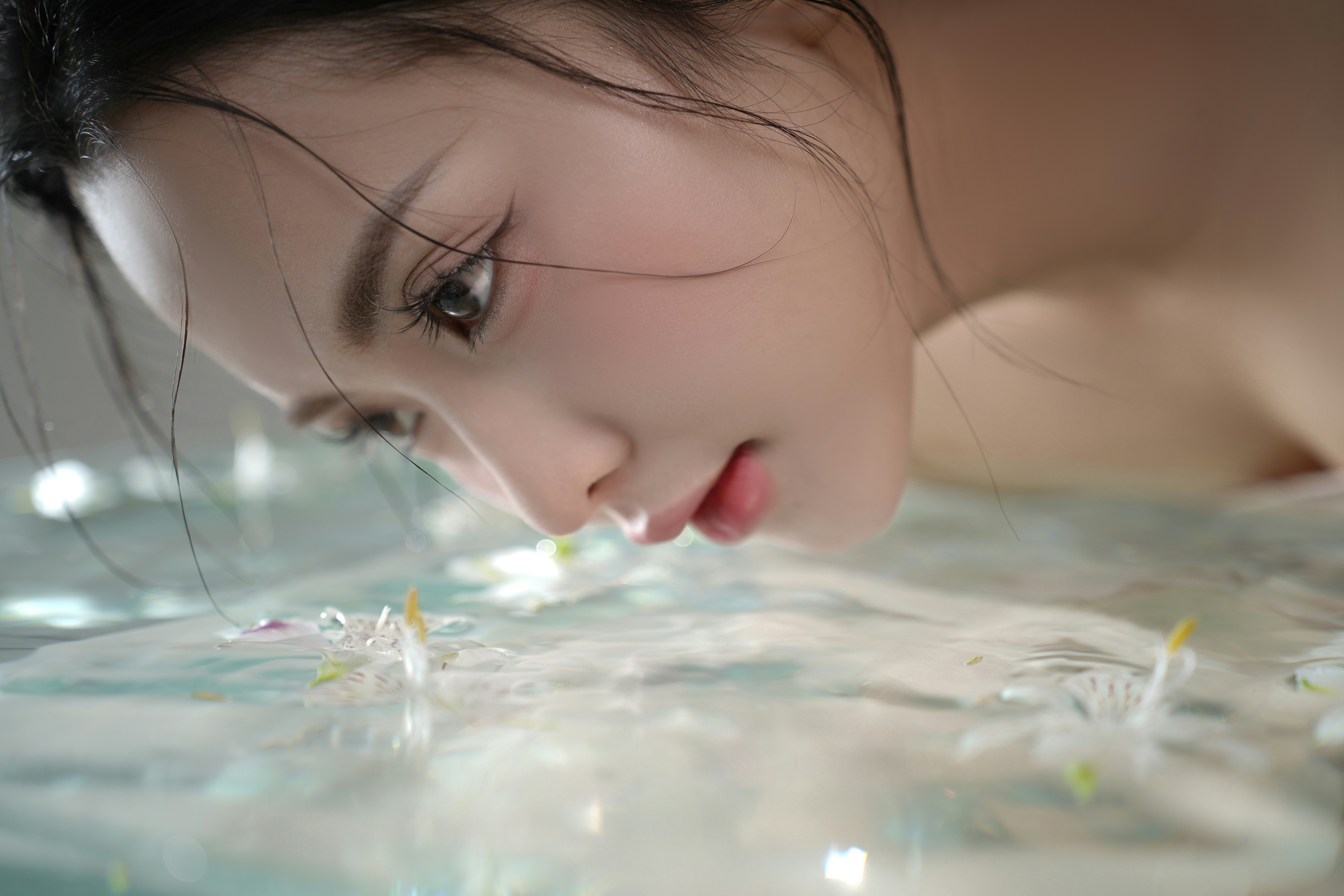 Close-up of a serene gaze: a delicate portrait near a water surface