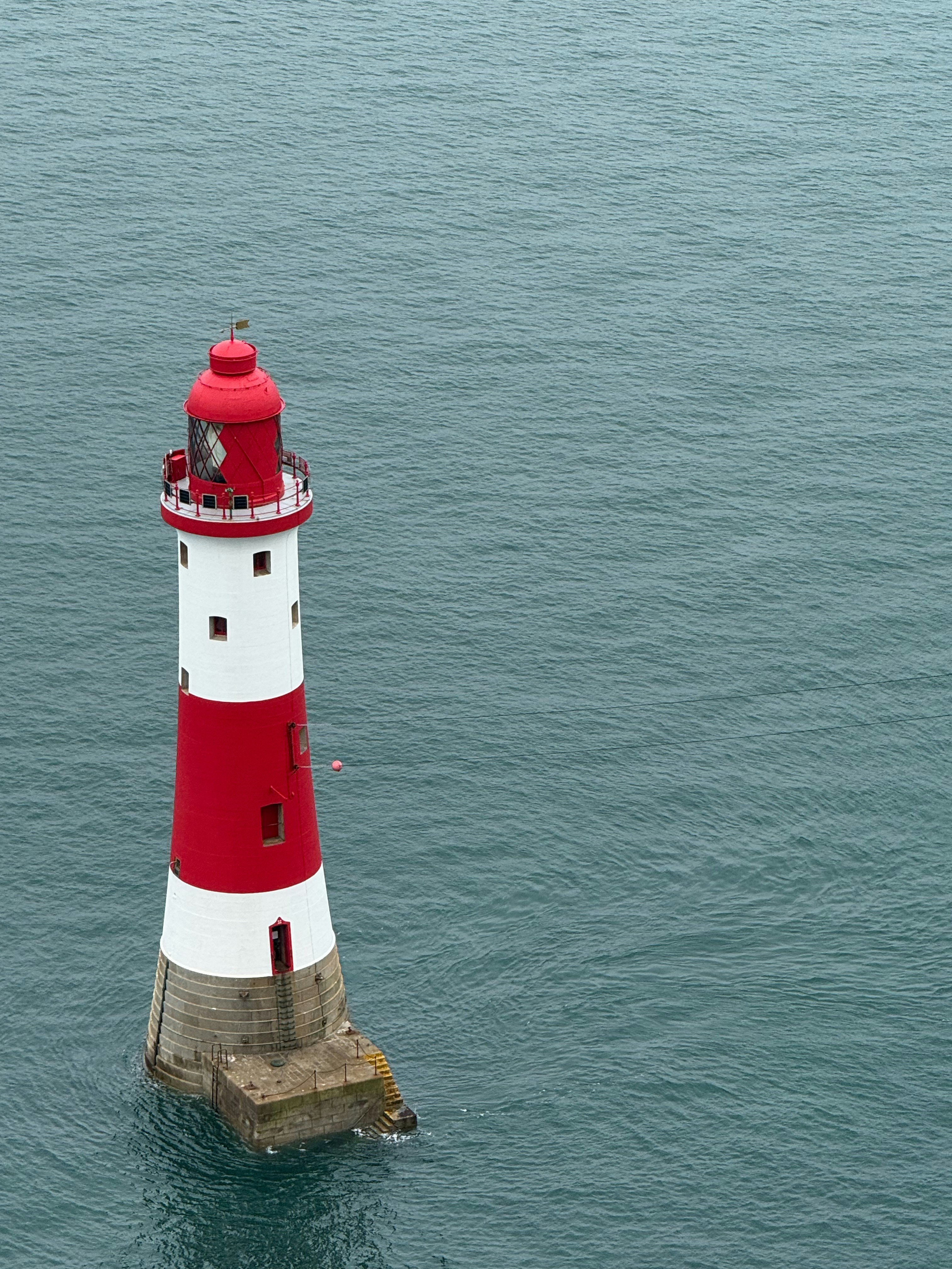 Red-Striped Beacon: A solitary lighthouse Poised in Quiet Seas