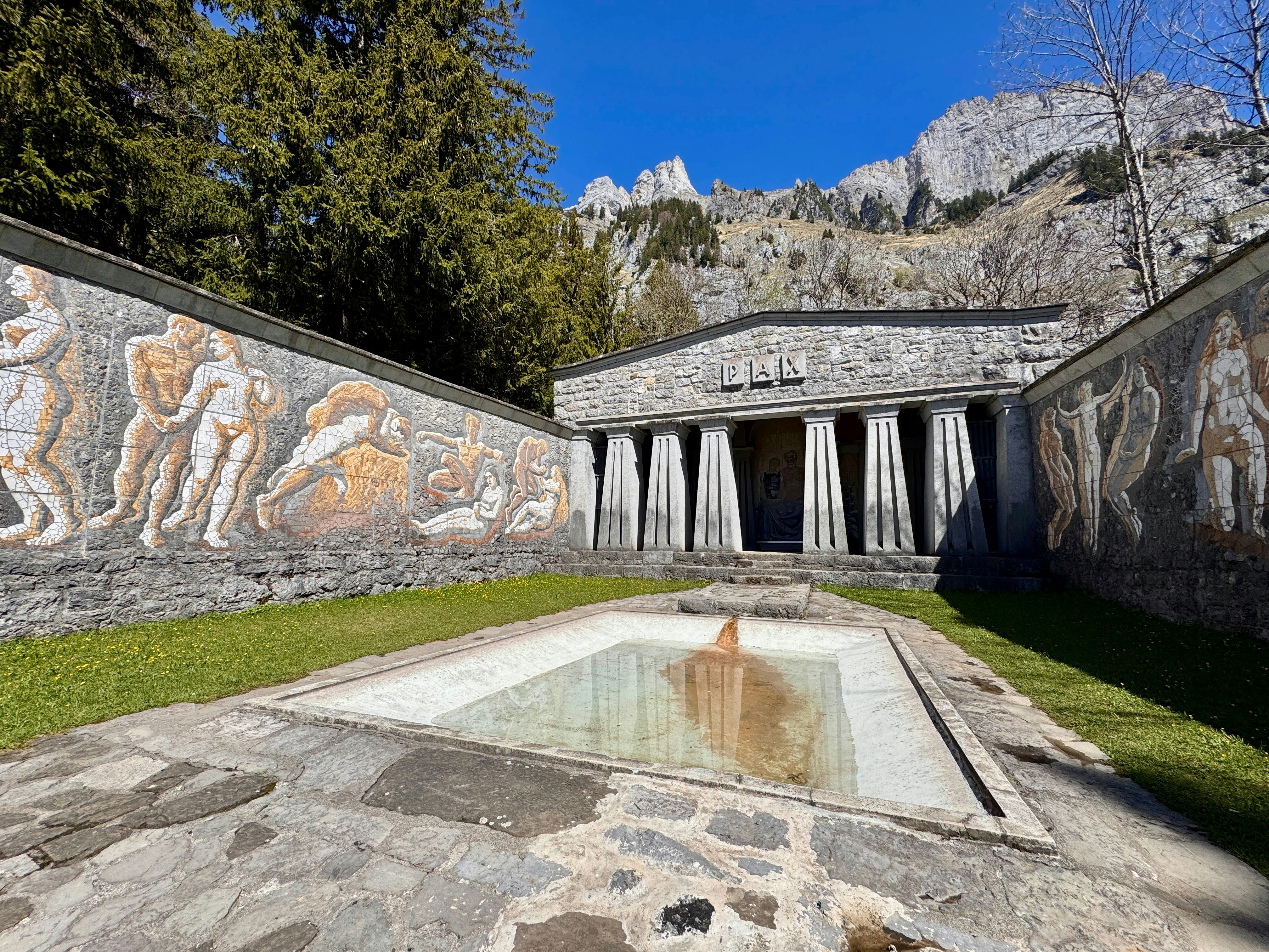 Carved Terrace Gateway: Mural Walls and Reflective Basin at an Alpine Memorial