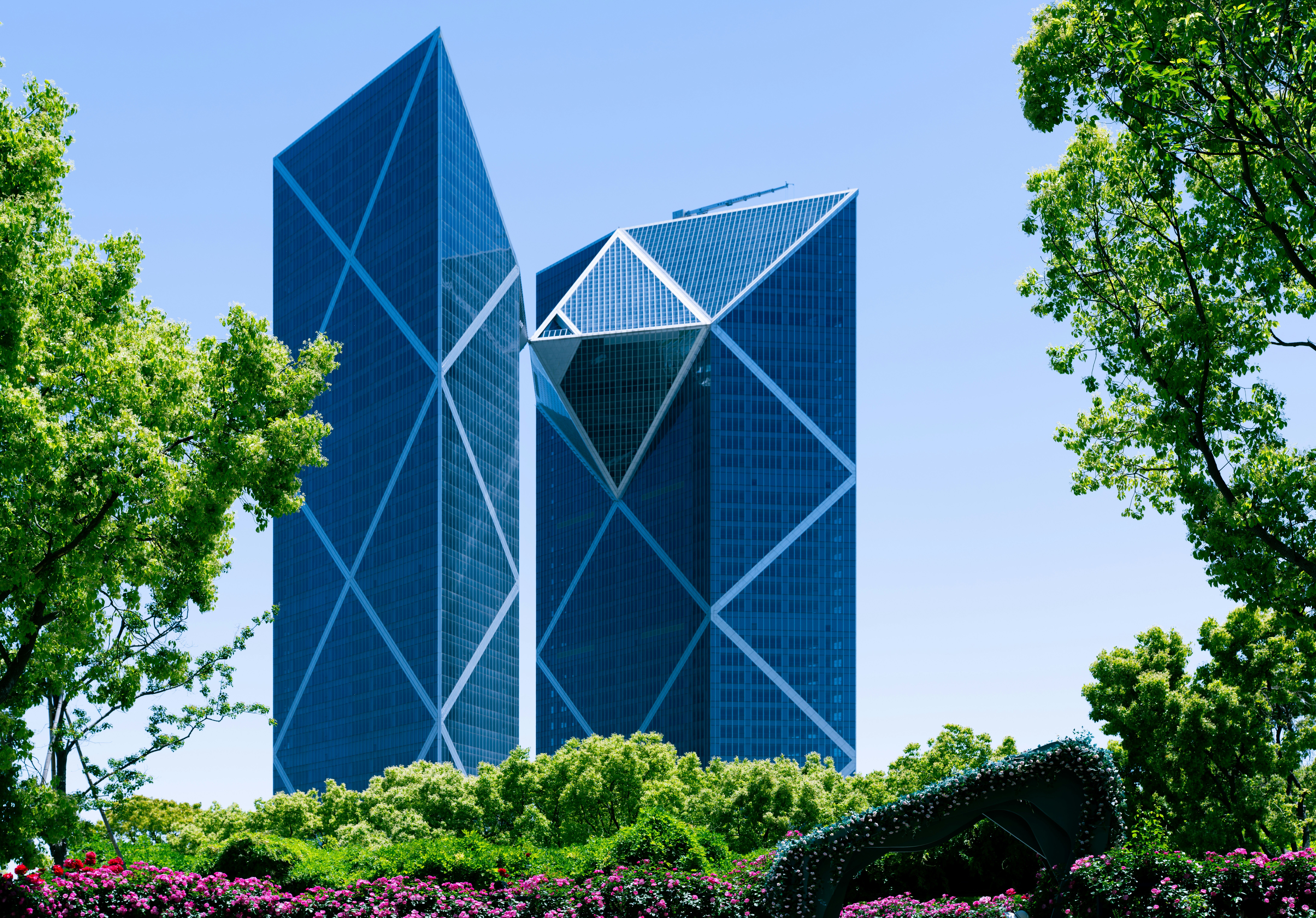 Skyward Facades: A Trio of Diamond-Crisscrossed Towers Rising Over Blooming Foreground