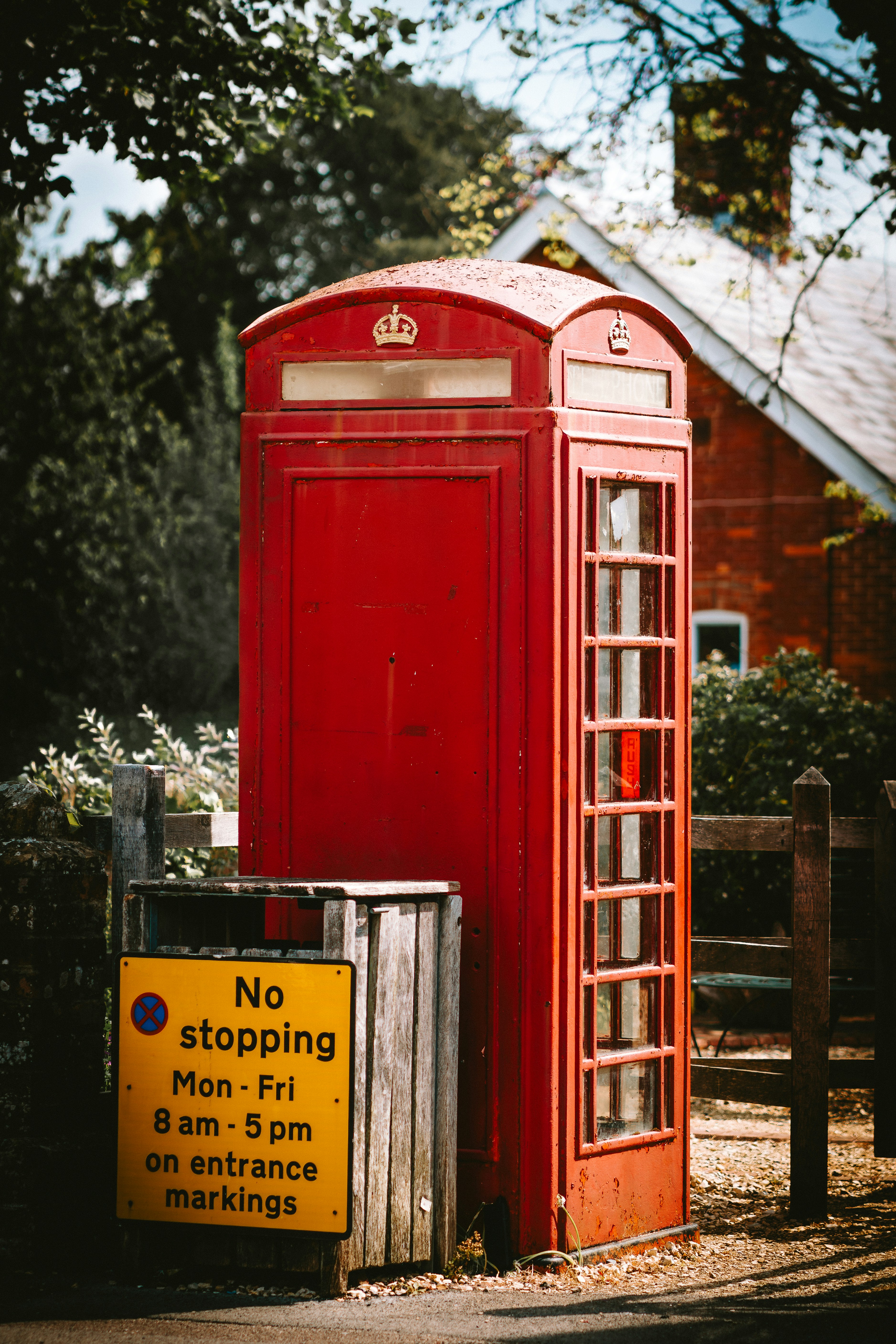 Red Ritual: A Classic British Telephone Box Guarded by a Quiet Yard Sign