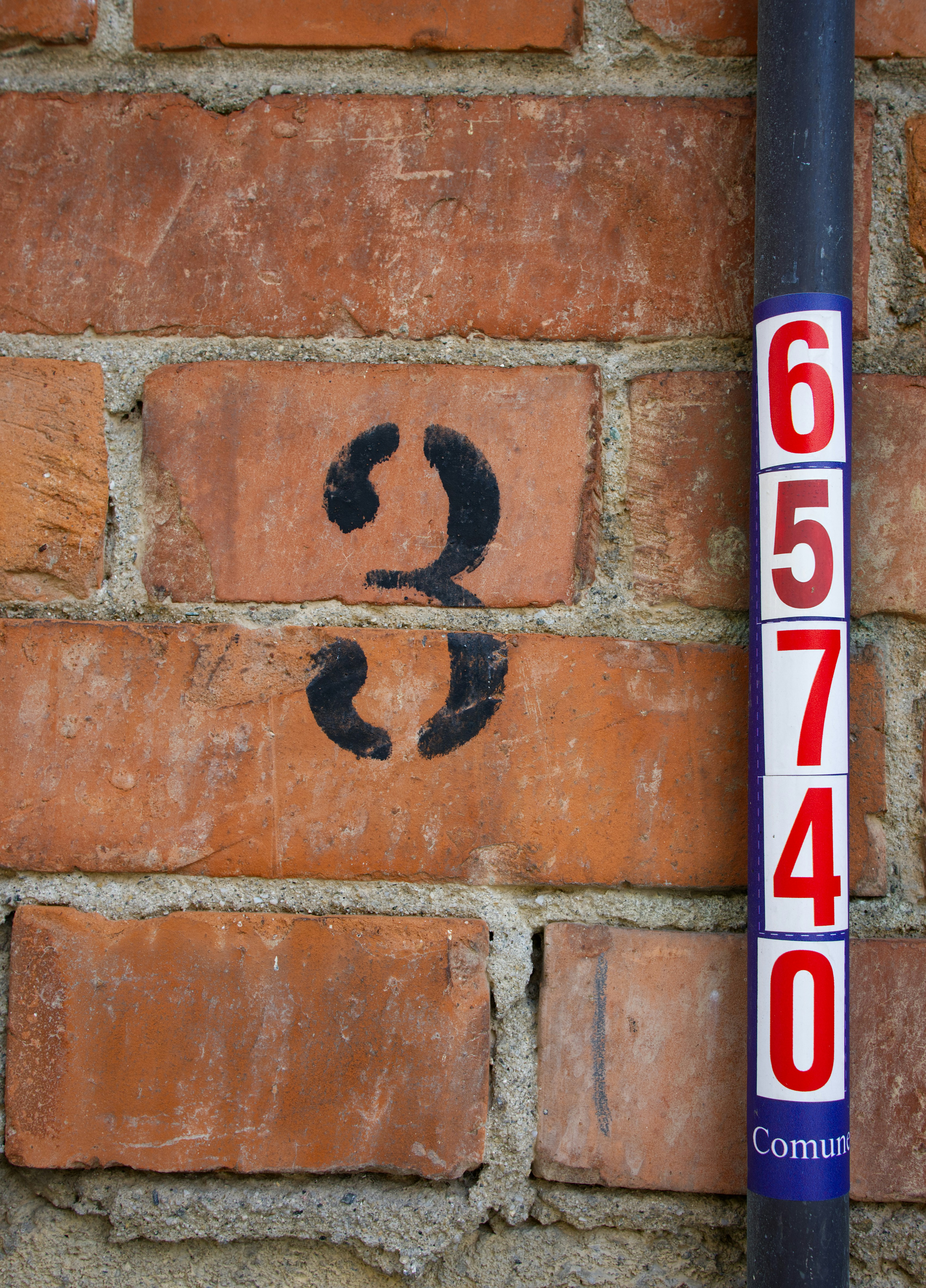 Vertical numbered pole beside a weathered brick wall