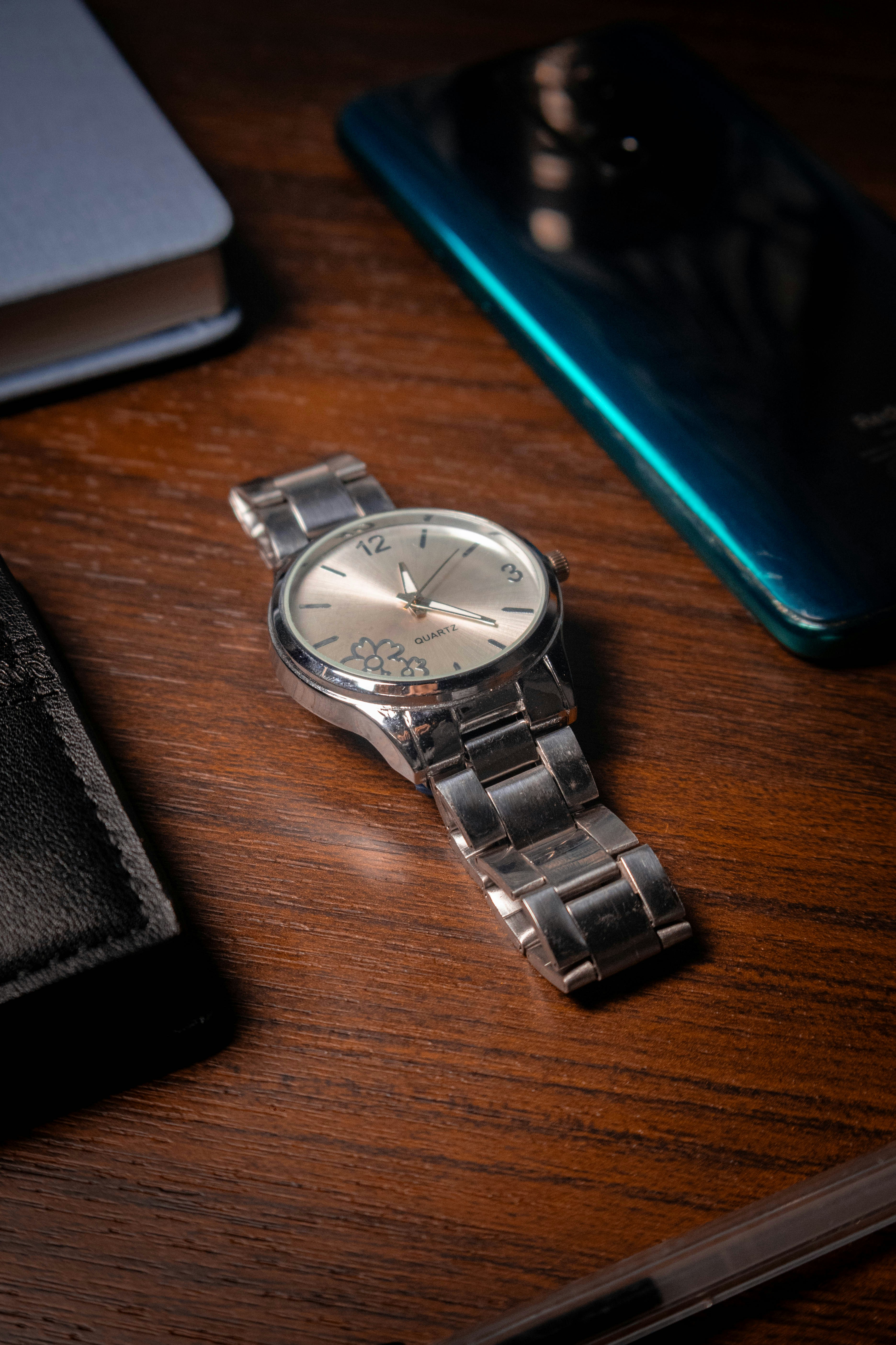 Silver Timepiece Among Tech and Leather