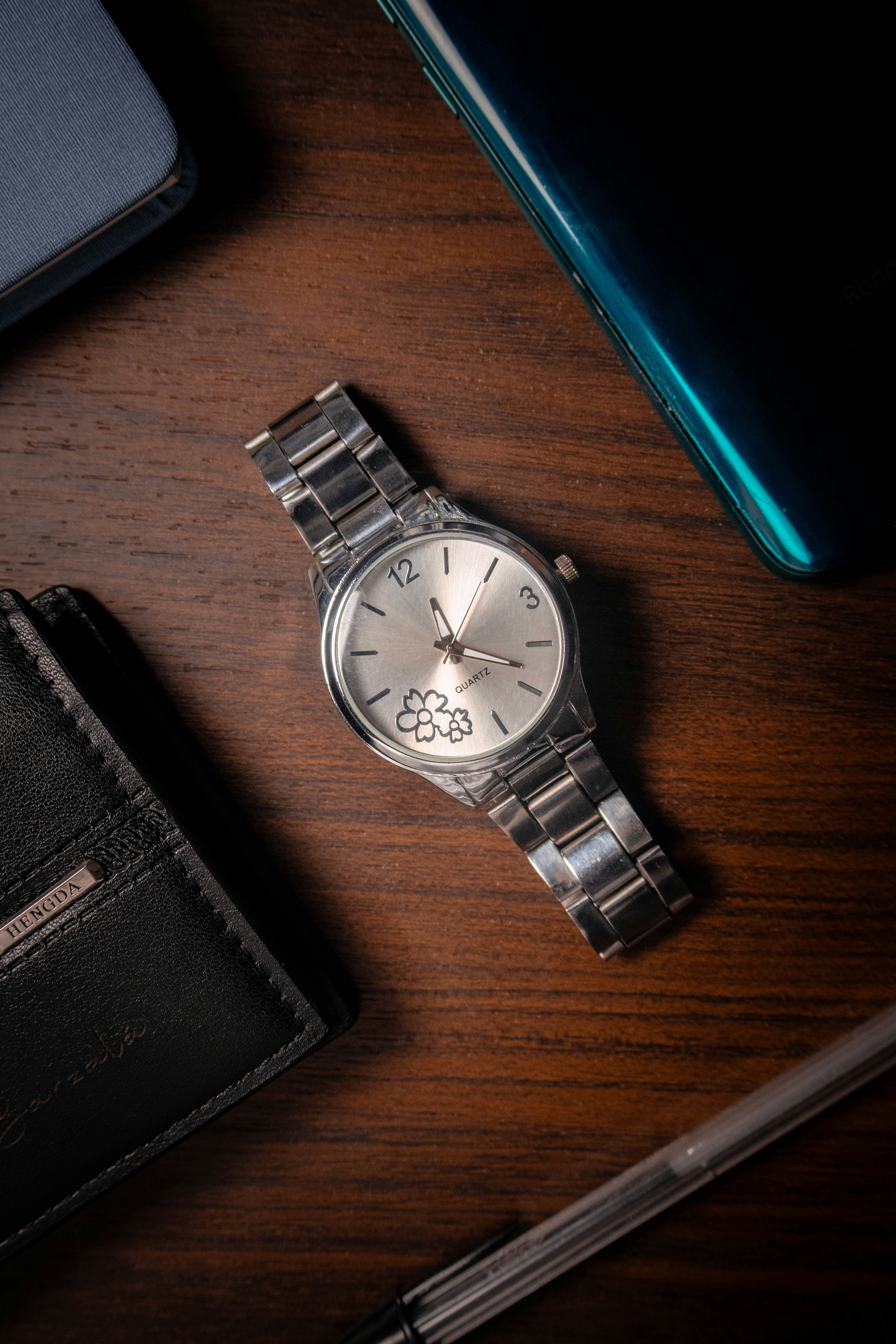 Metallic Timekeeper resting among gadgets on a wooden desk