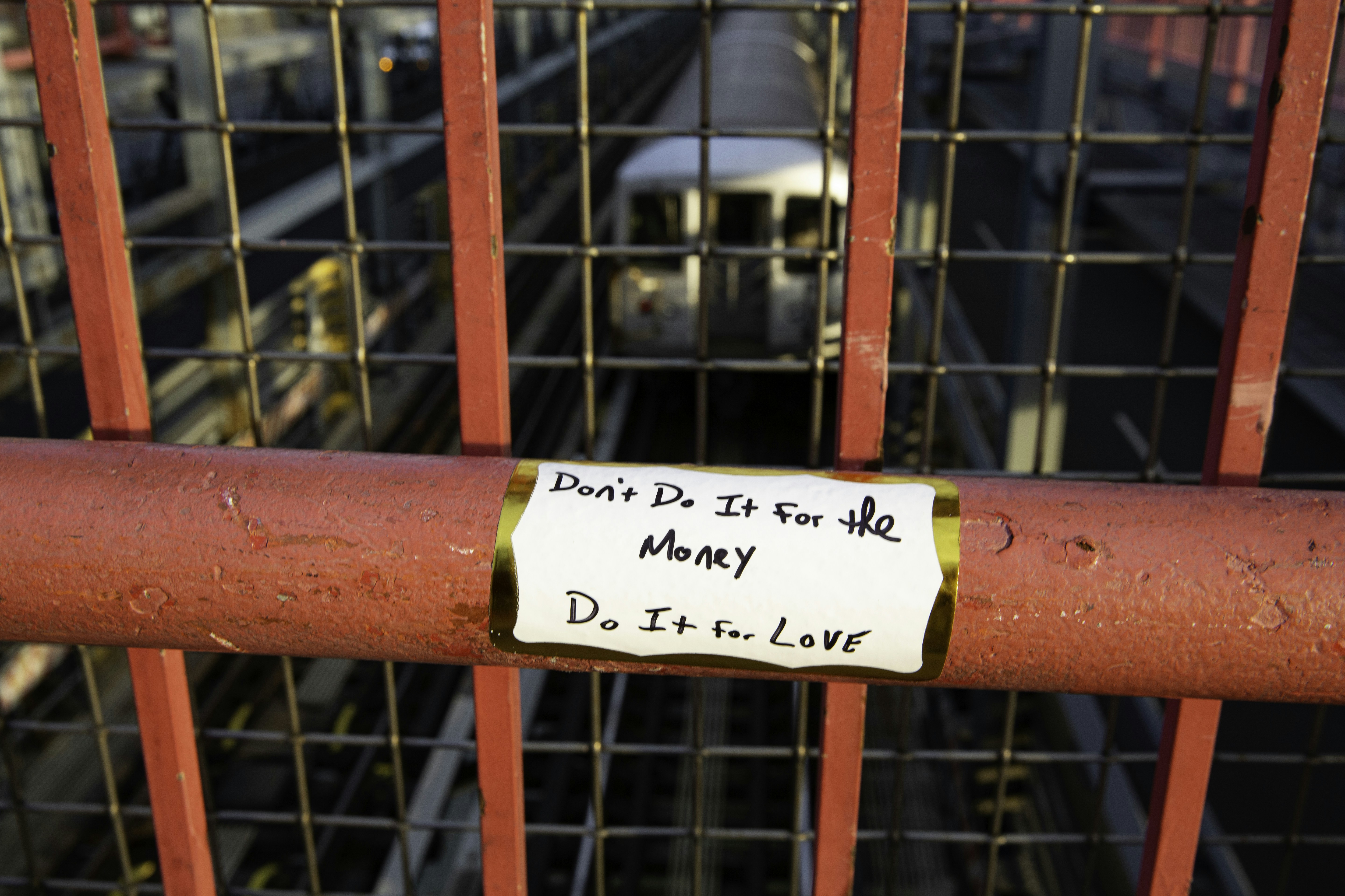 Sticky note on a red railing: a message of loyalty in concrete urban gridlock