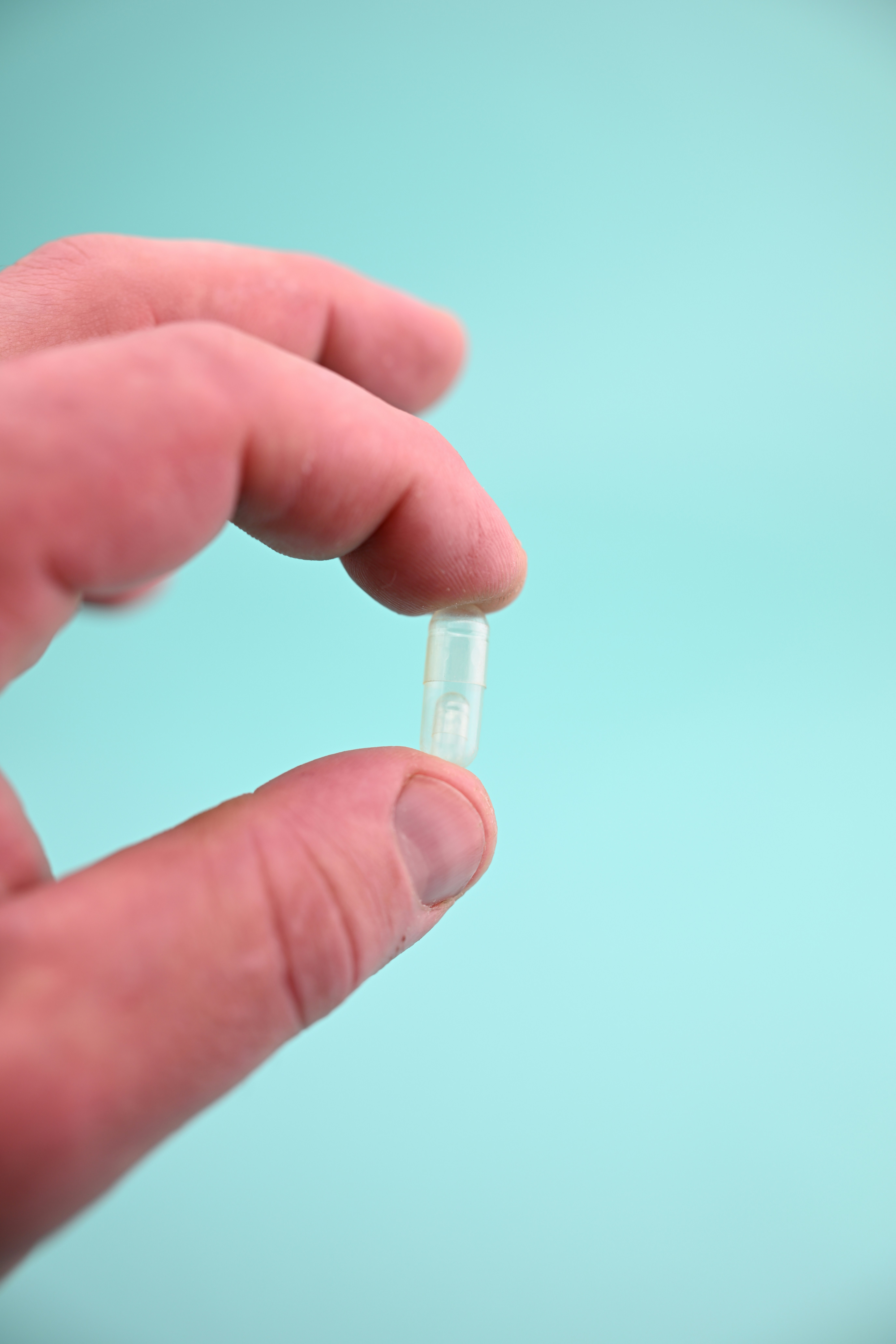 Tiny Capsule Between Fingers: A Delicate Moment of Precision