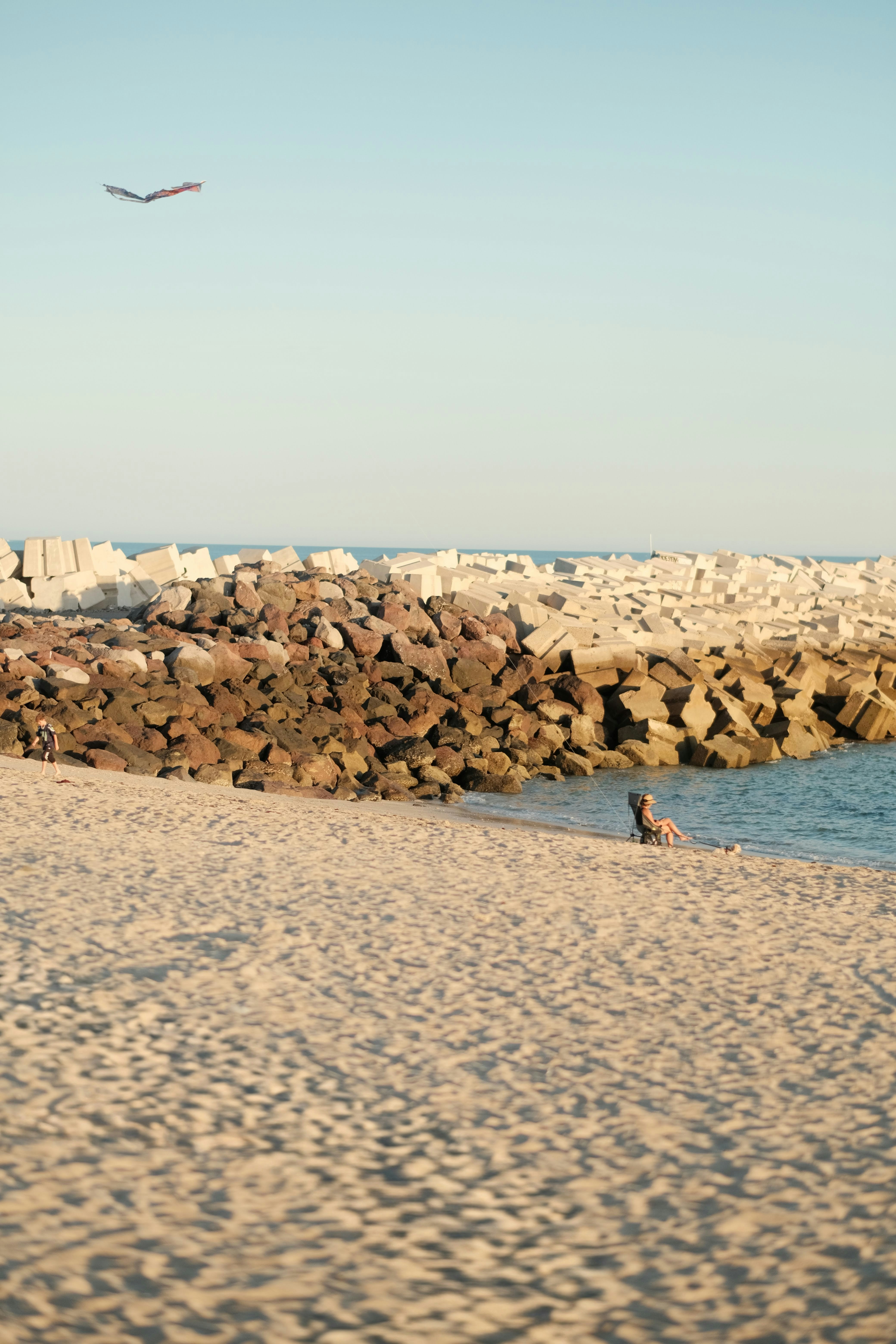 Seaside Quiet: A Lone Figures Rest on the Shore Beneath a Far-Reaching Sky