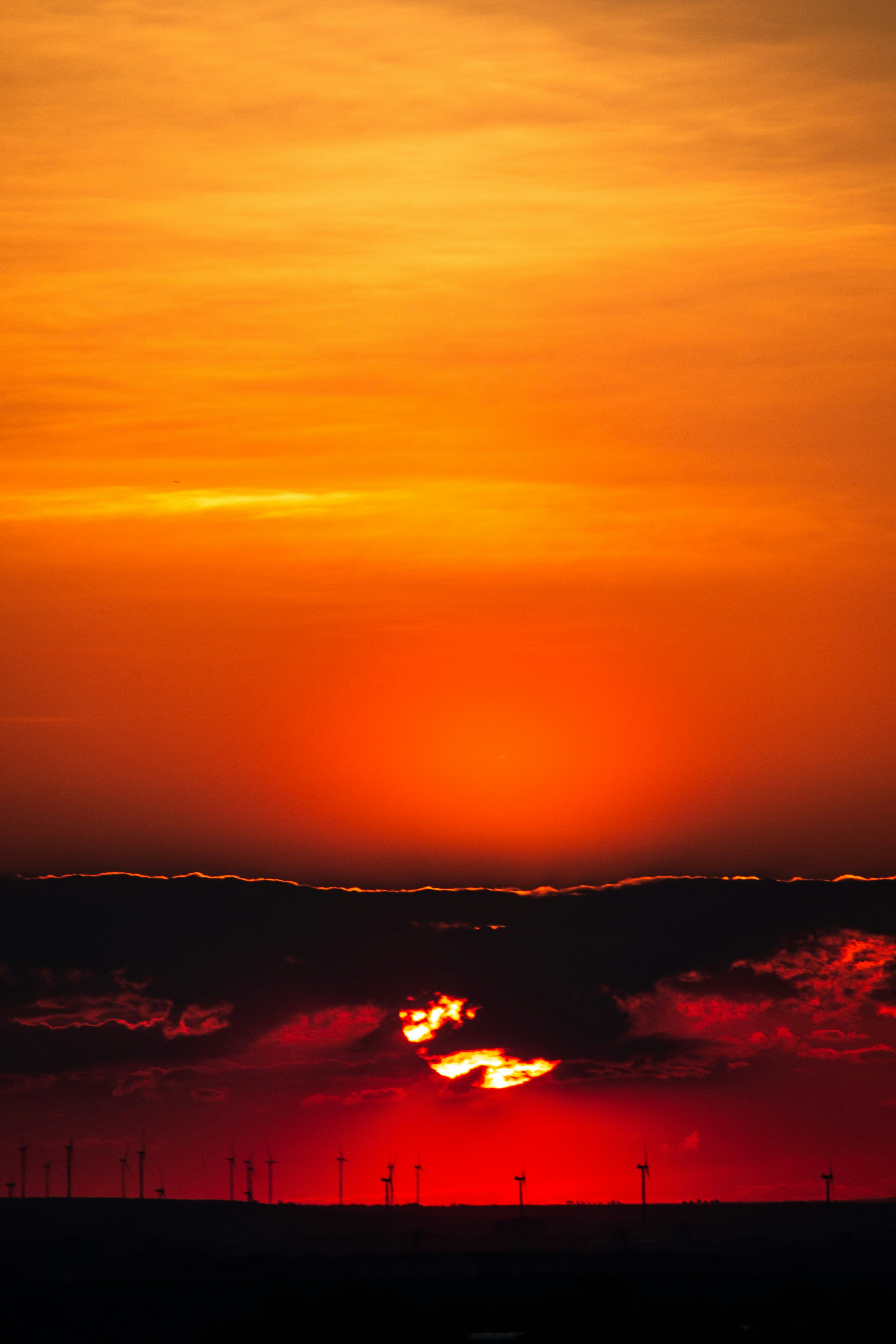 Crimson Horizon: Sunset Sink over Distant Silhouettes