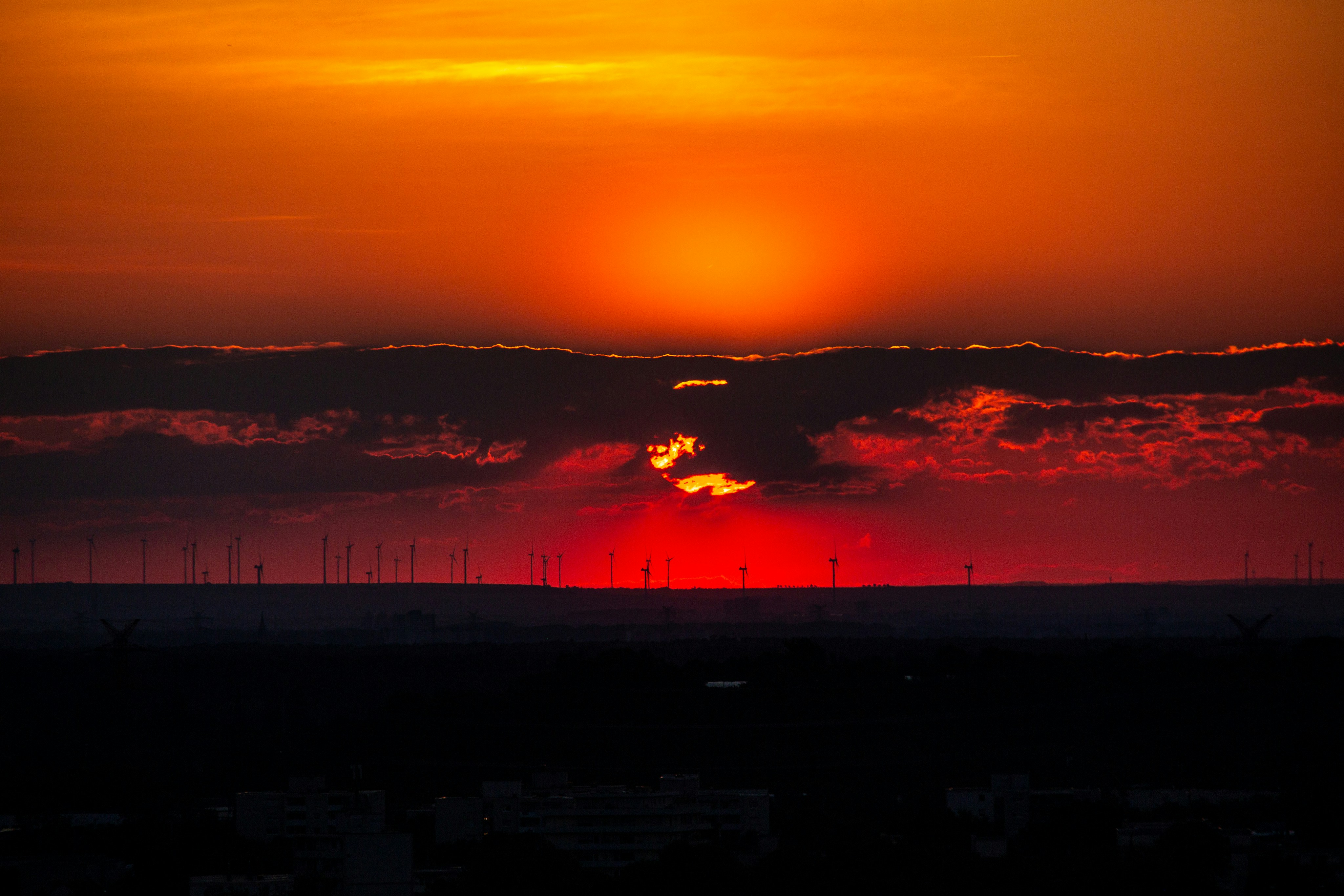 Crimson Horizon: Sun Bleeds Over Silent Wind Turbines