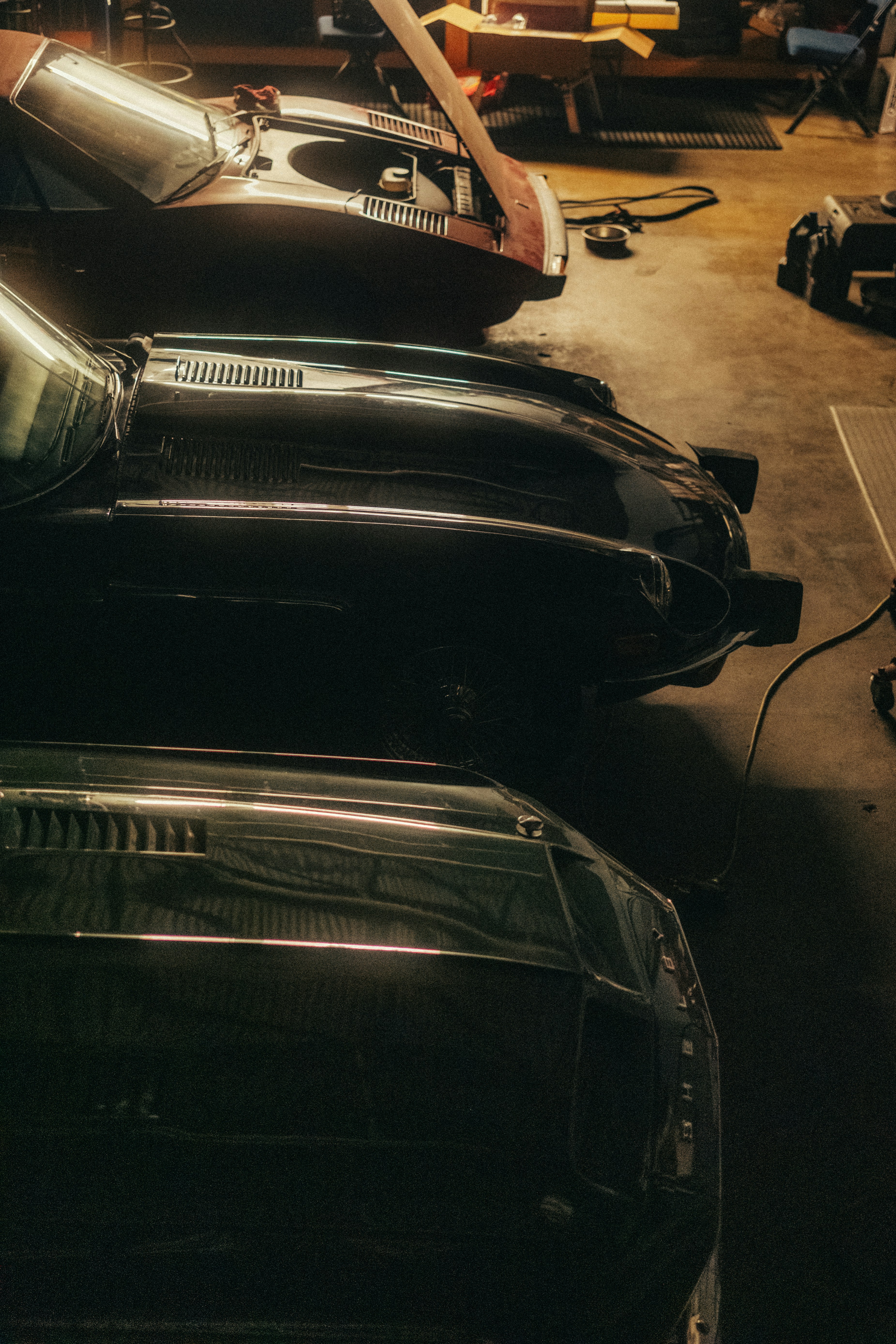 Lineup in the Dim Garage: Classic Cars Resting under Workbench Lights