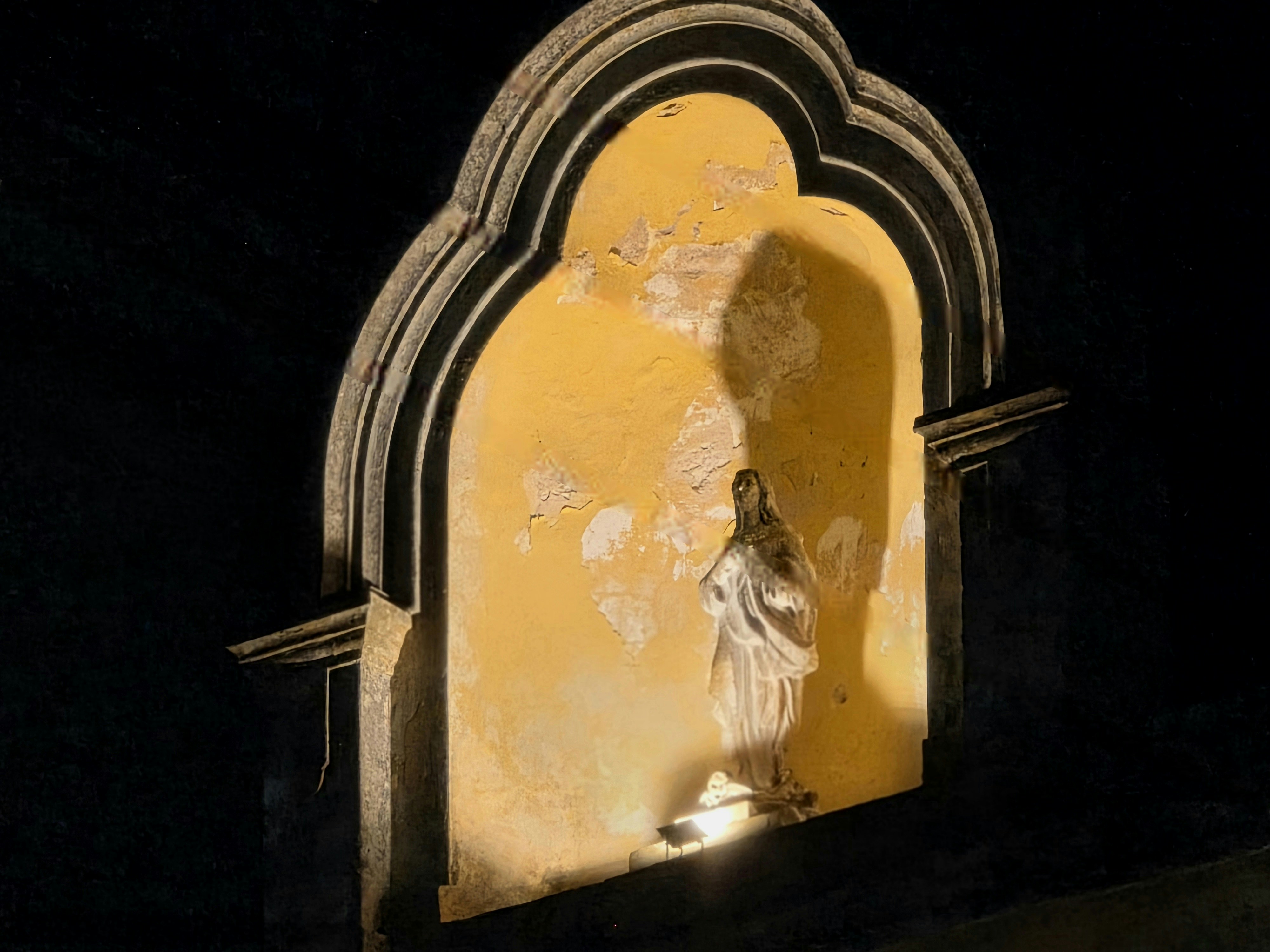 Soft Glow of a Figurine Niche in Moonlit Archway