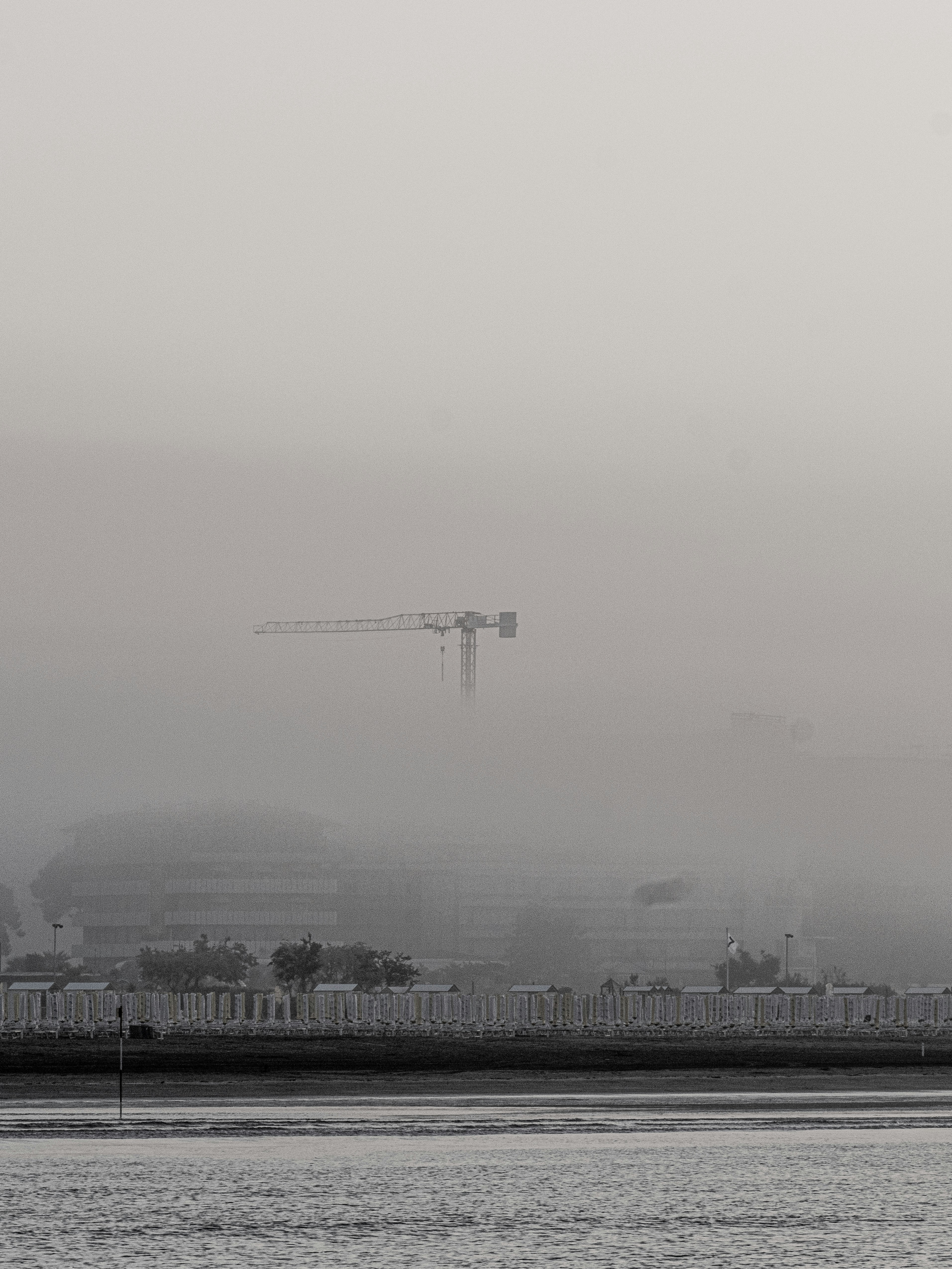 Mist Over the Harbor: Crane Silhouette in Distant Fog