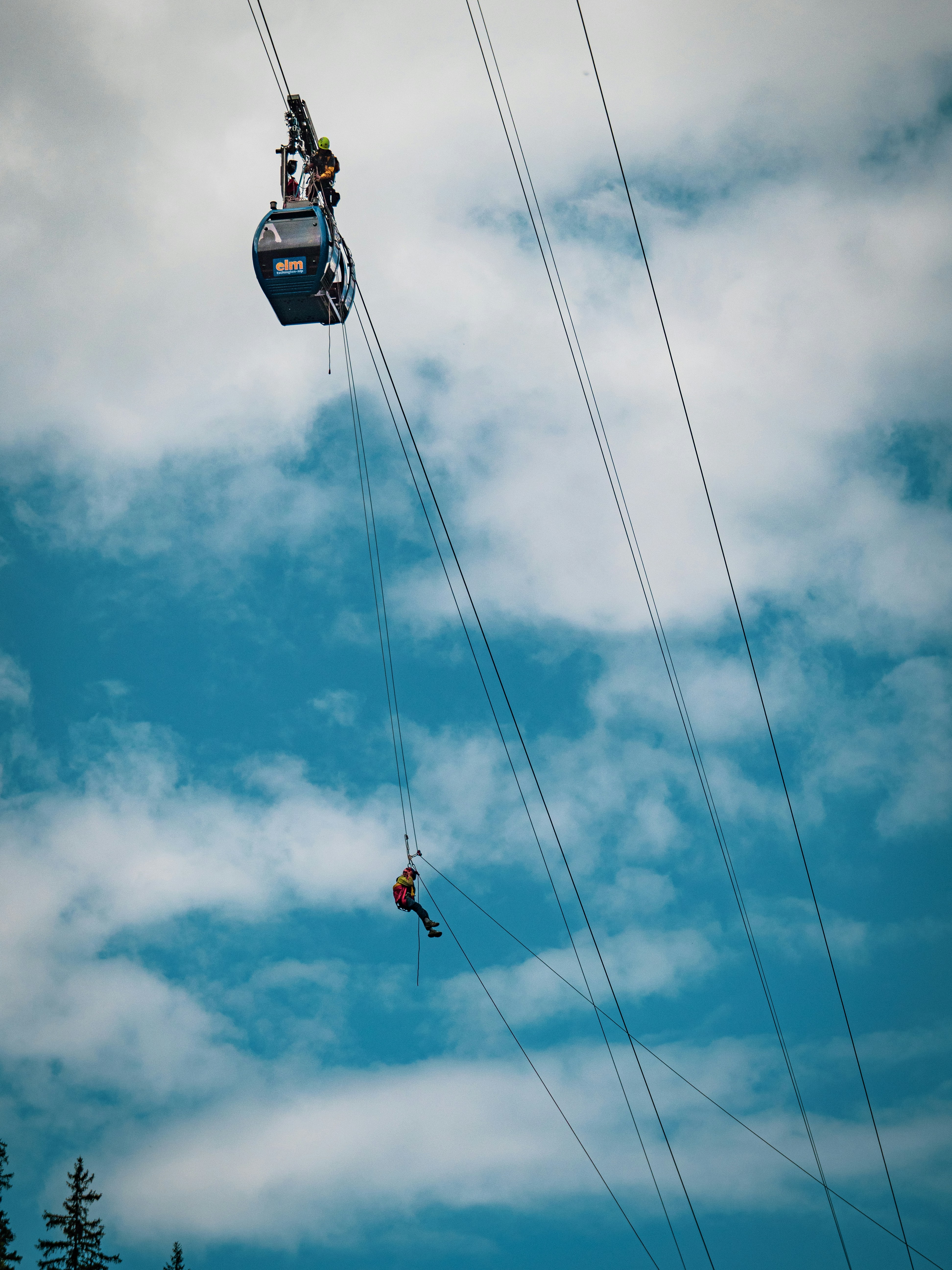 High-Altitude Rescue: A Cable Car Climber in a Sky-Blue Expanse