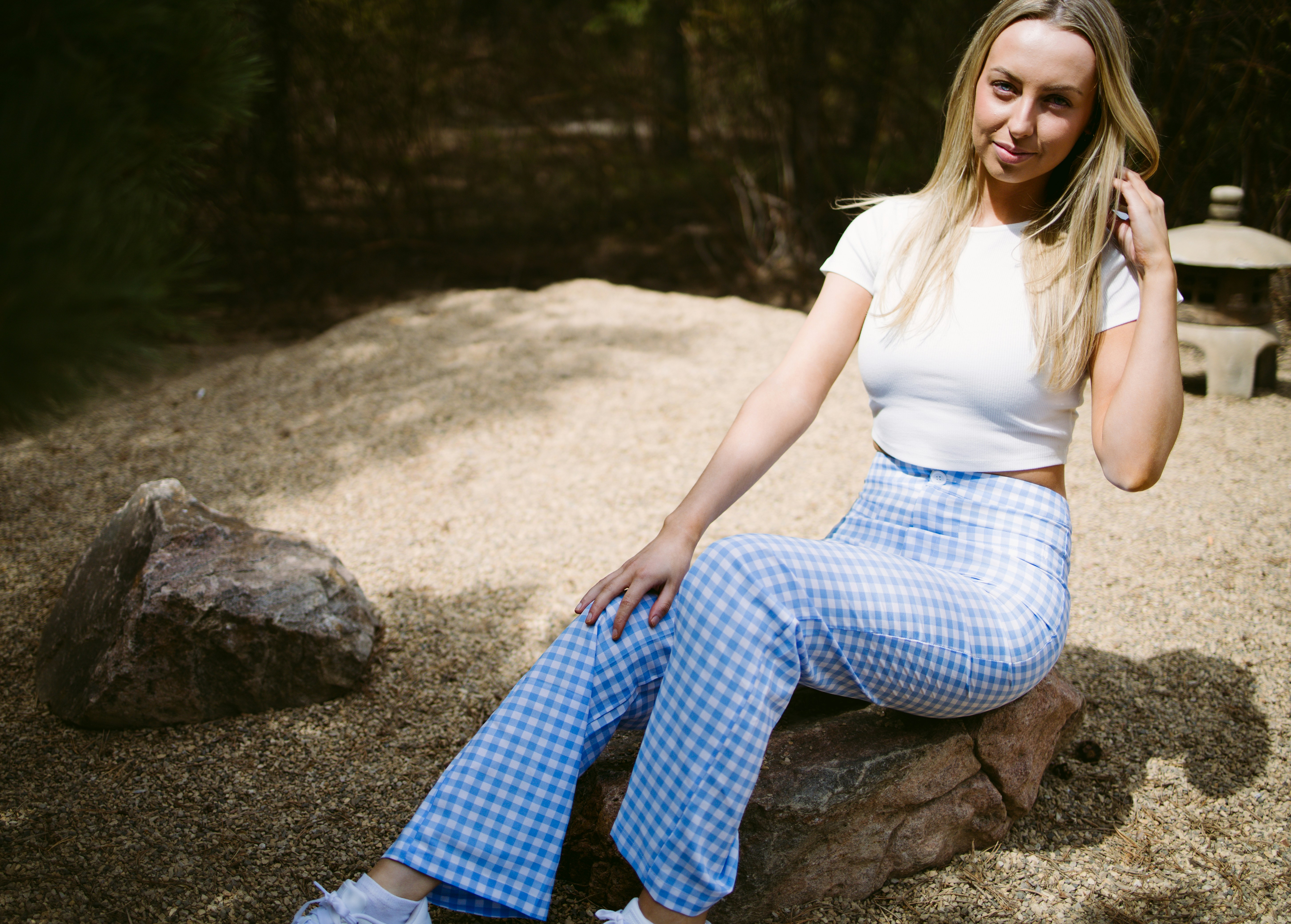 Relaxed portrait on a sunlit rock bench in a garden setting