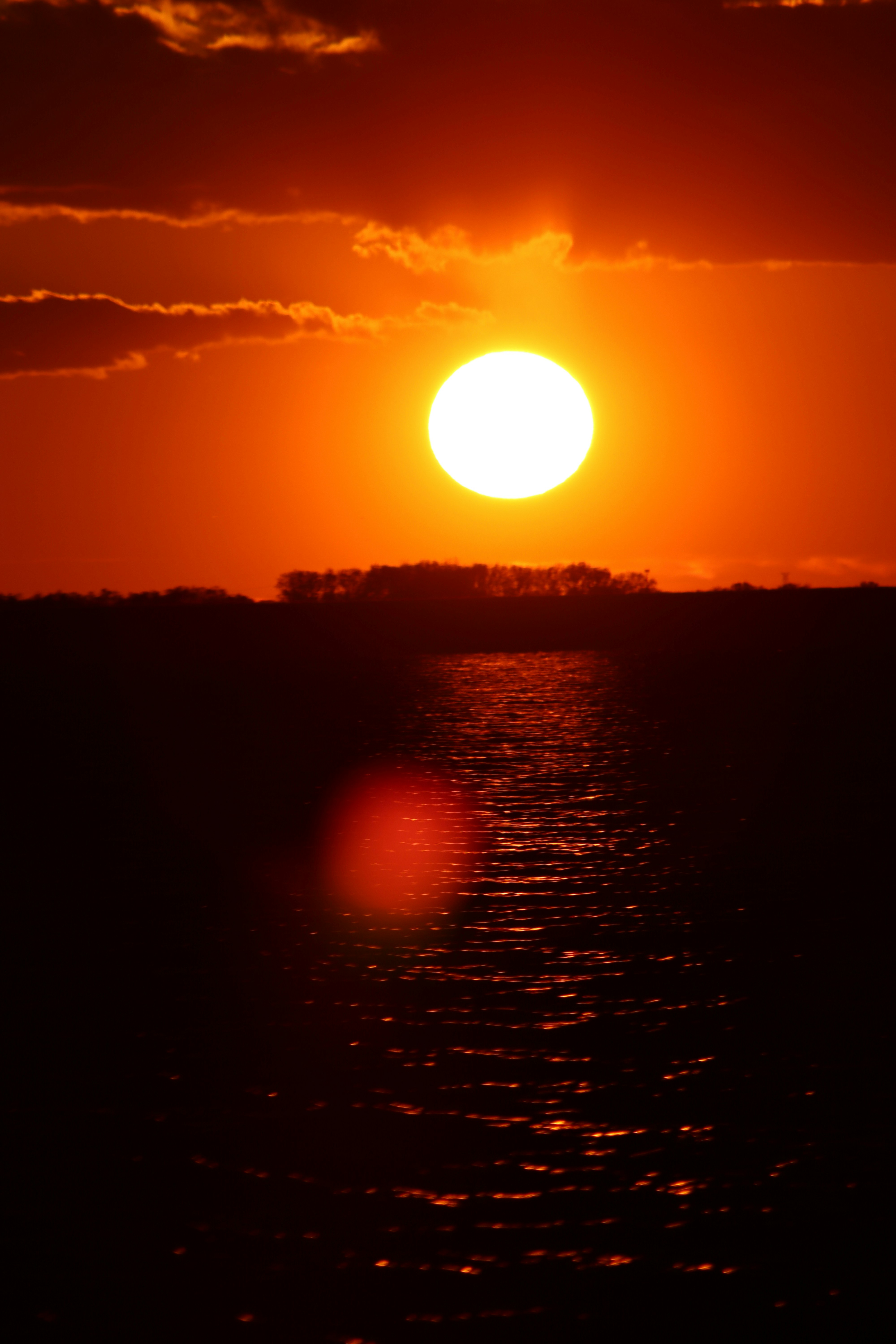 Sunlit Horizon: A Crimson Dusk Over Calm Waters