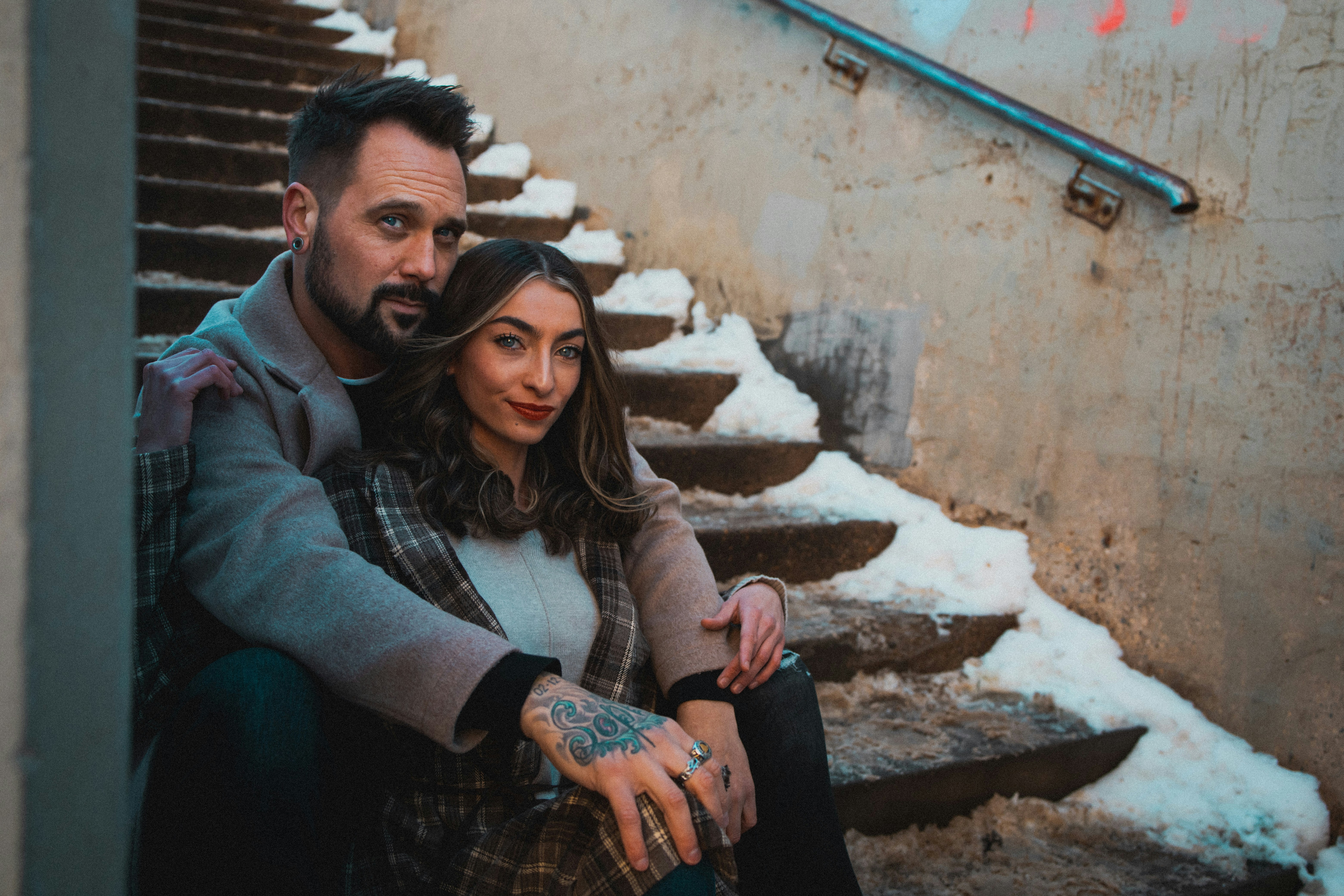 Cozy confidants on cold stairs: warm embrace beneath winter light