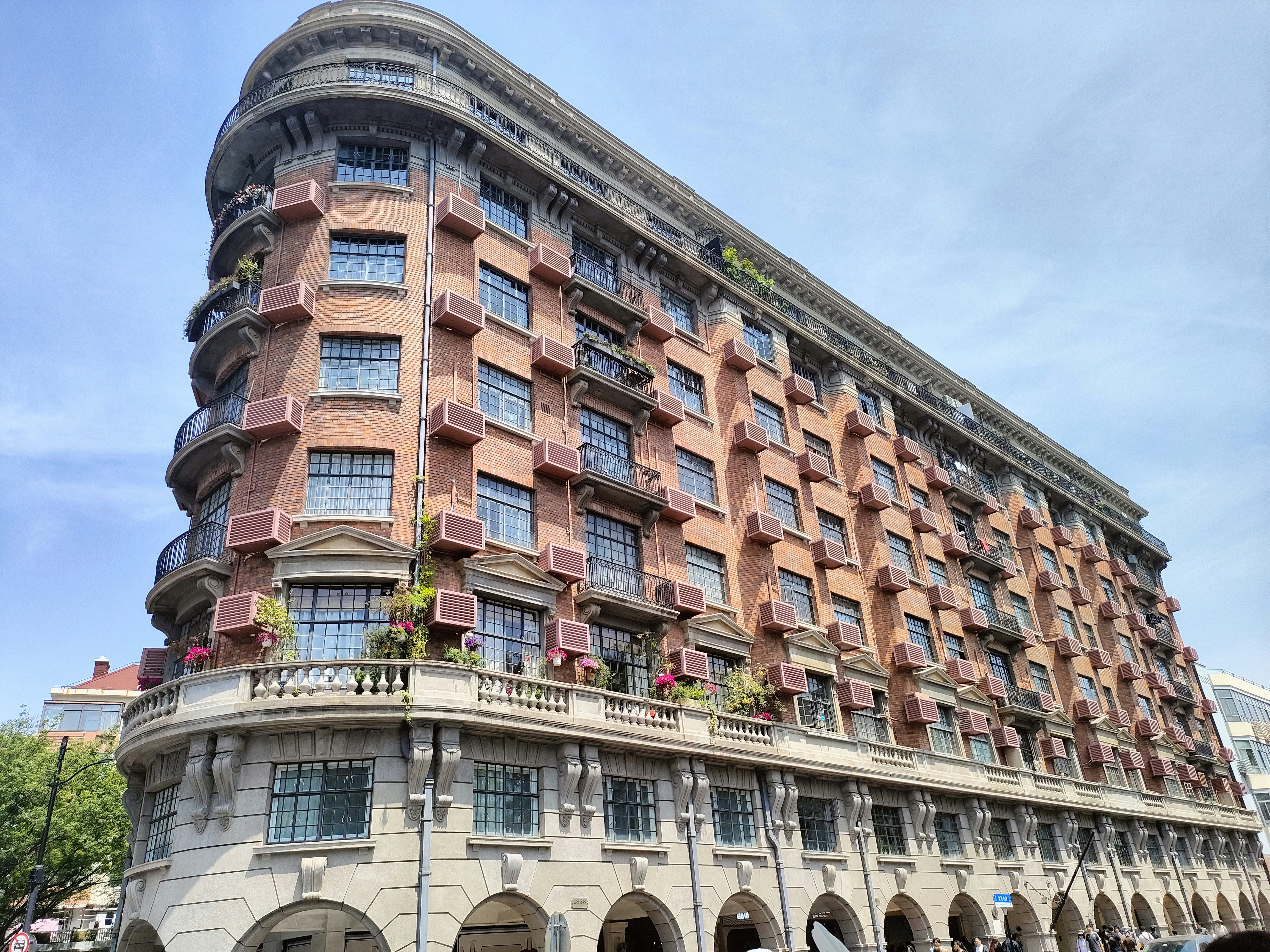Historic brick building with arched ground floor and balconies.