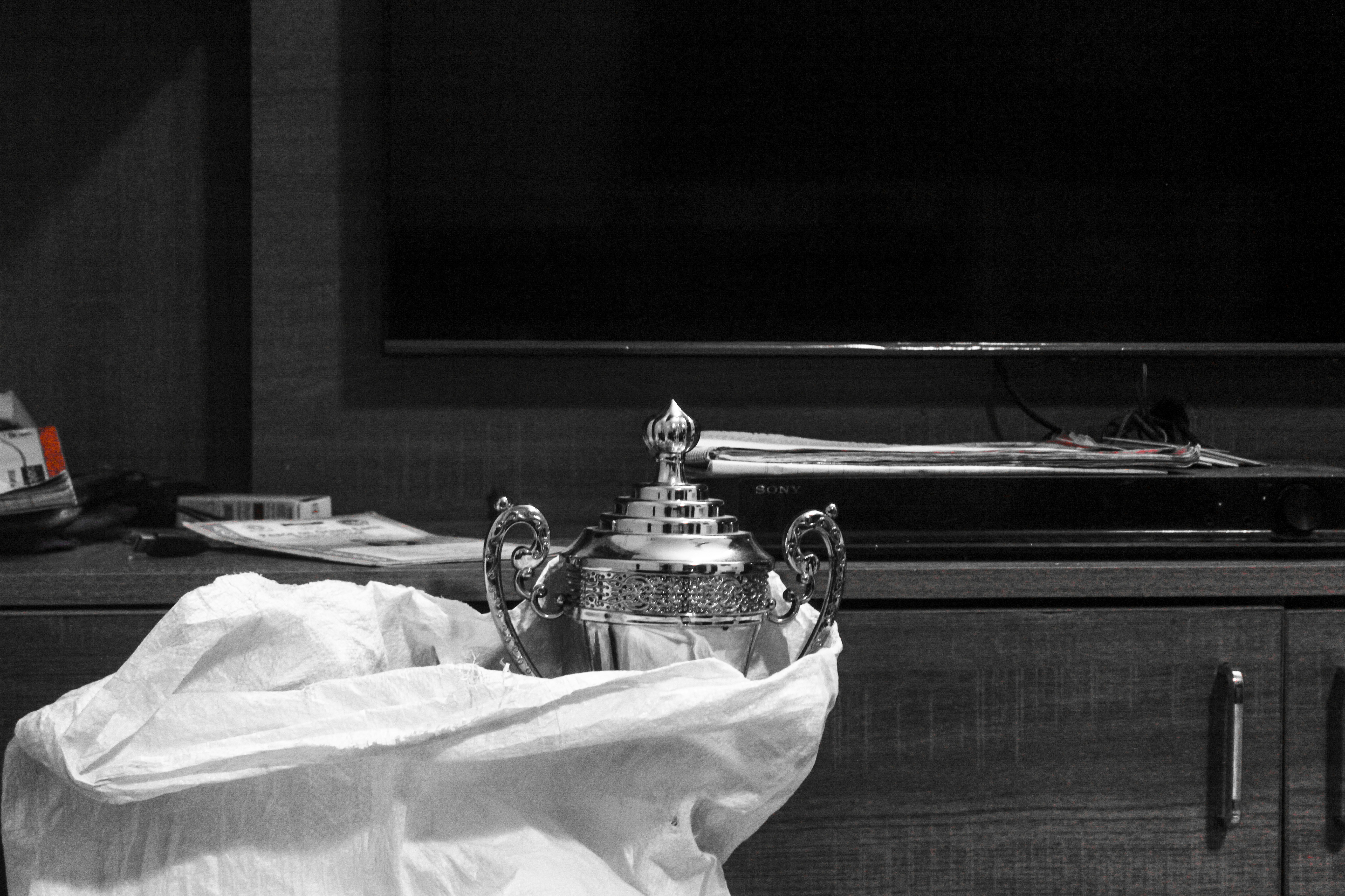 Silver Trophy on a White Draped Cloth Amid a Dark Cabinet Scene