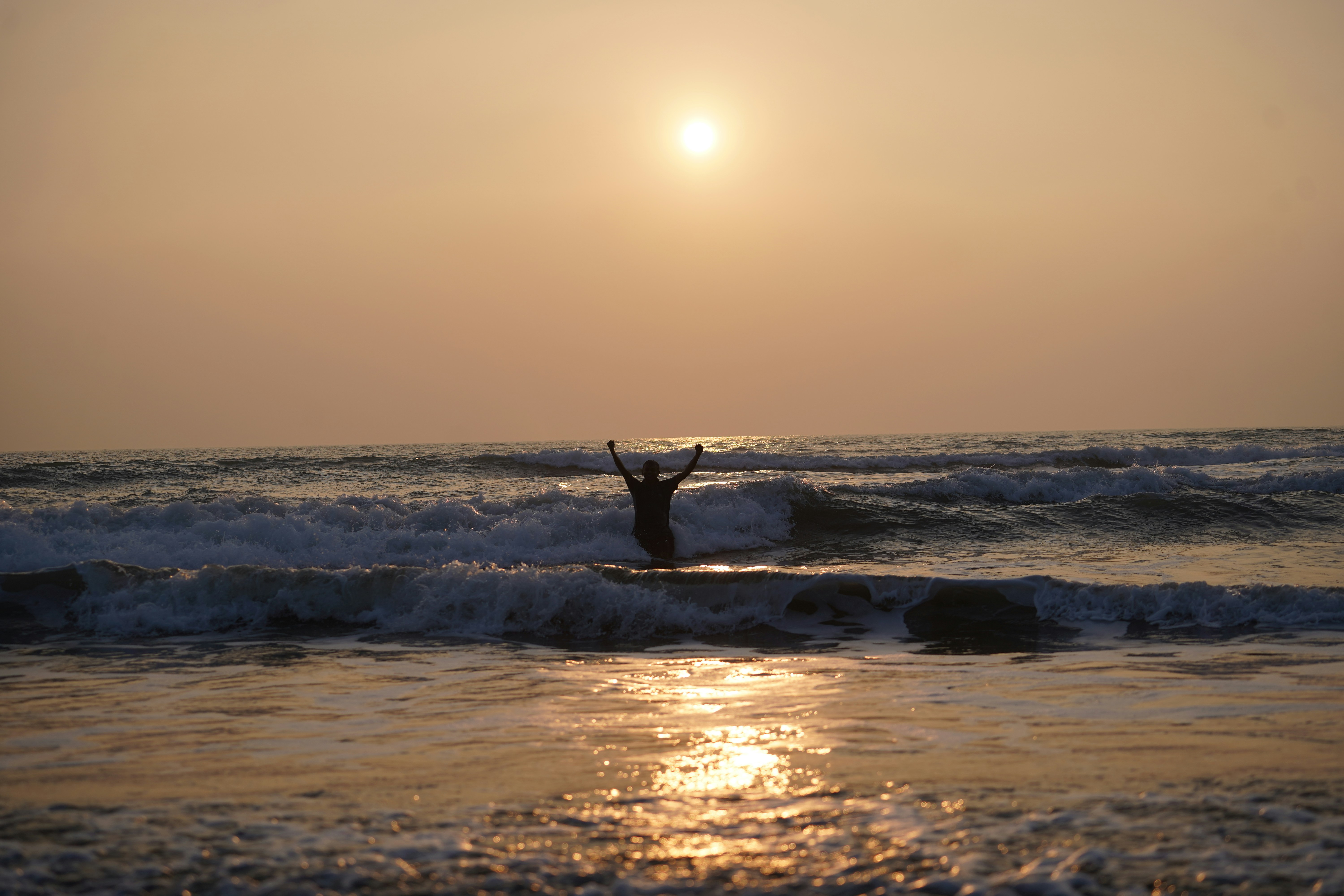 Sunlit Surge: A Silhouetted Figure Celebrates at the Crest of the Sea