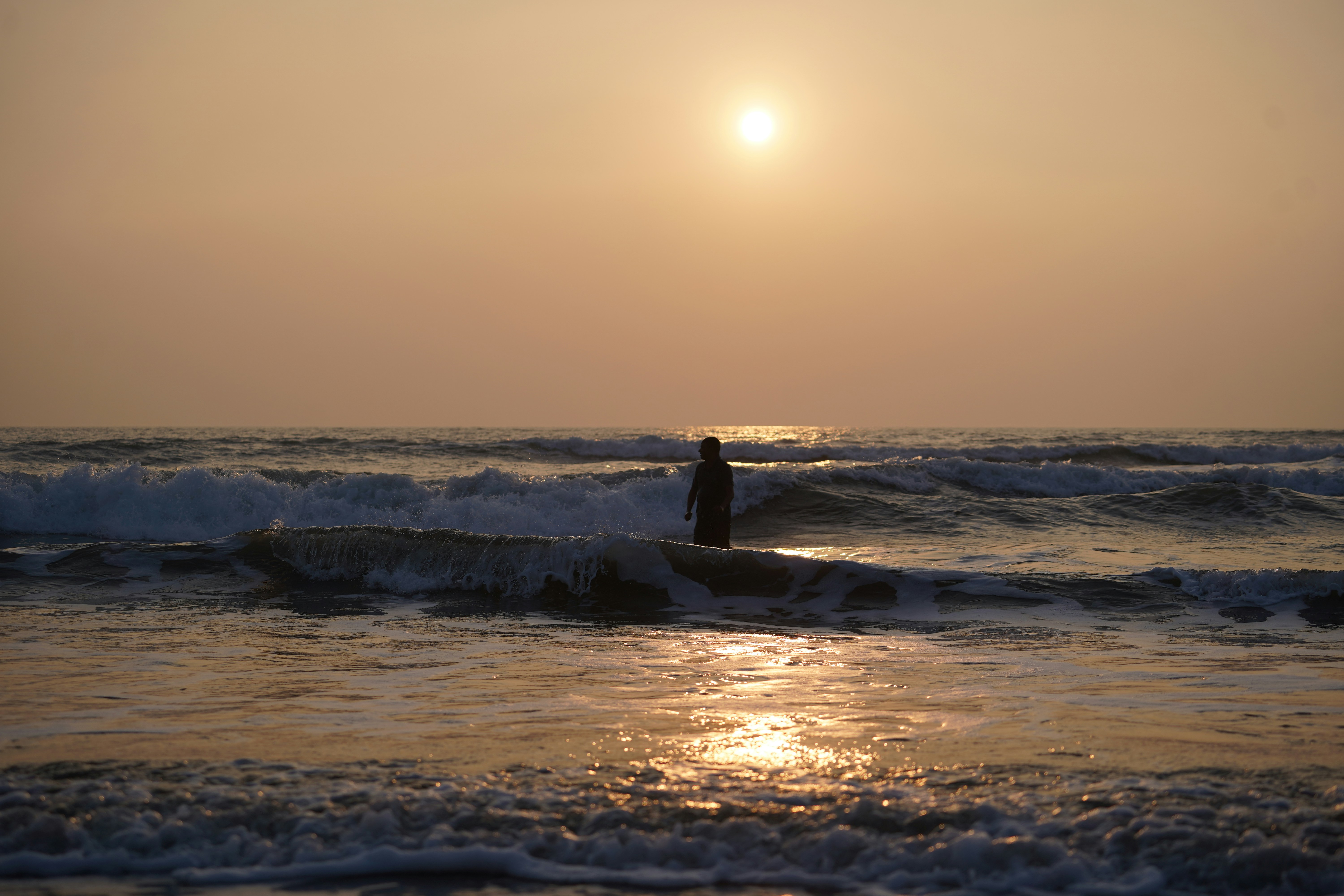 Silhouette at Sunset: A lone surfer watches the last glow