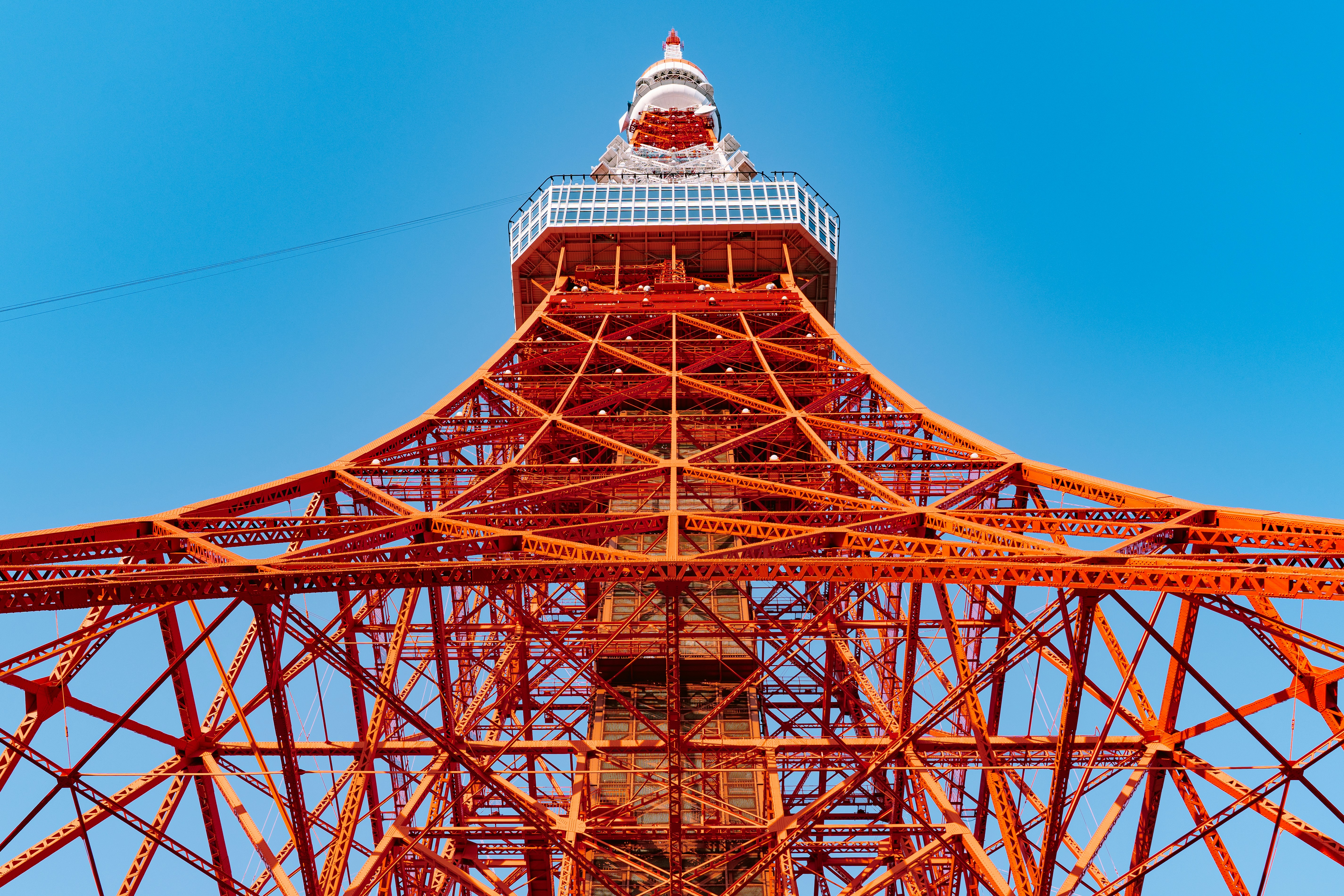 Fiery lattice: close-up of Tokyo Tower’s intricate steelwork above the blue