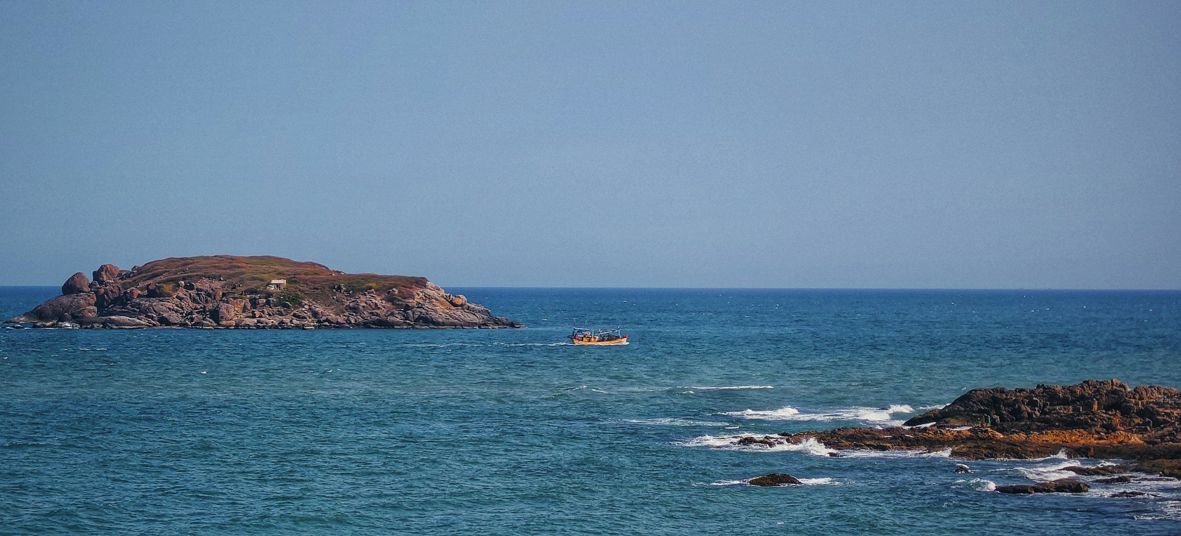 Coastal Horizon: A Quiet Boat Near Rocky Island