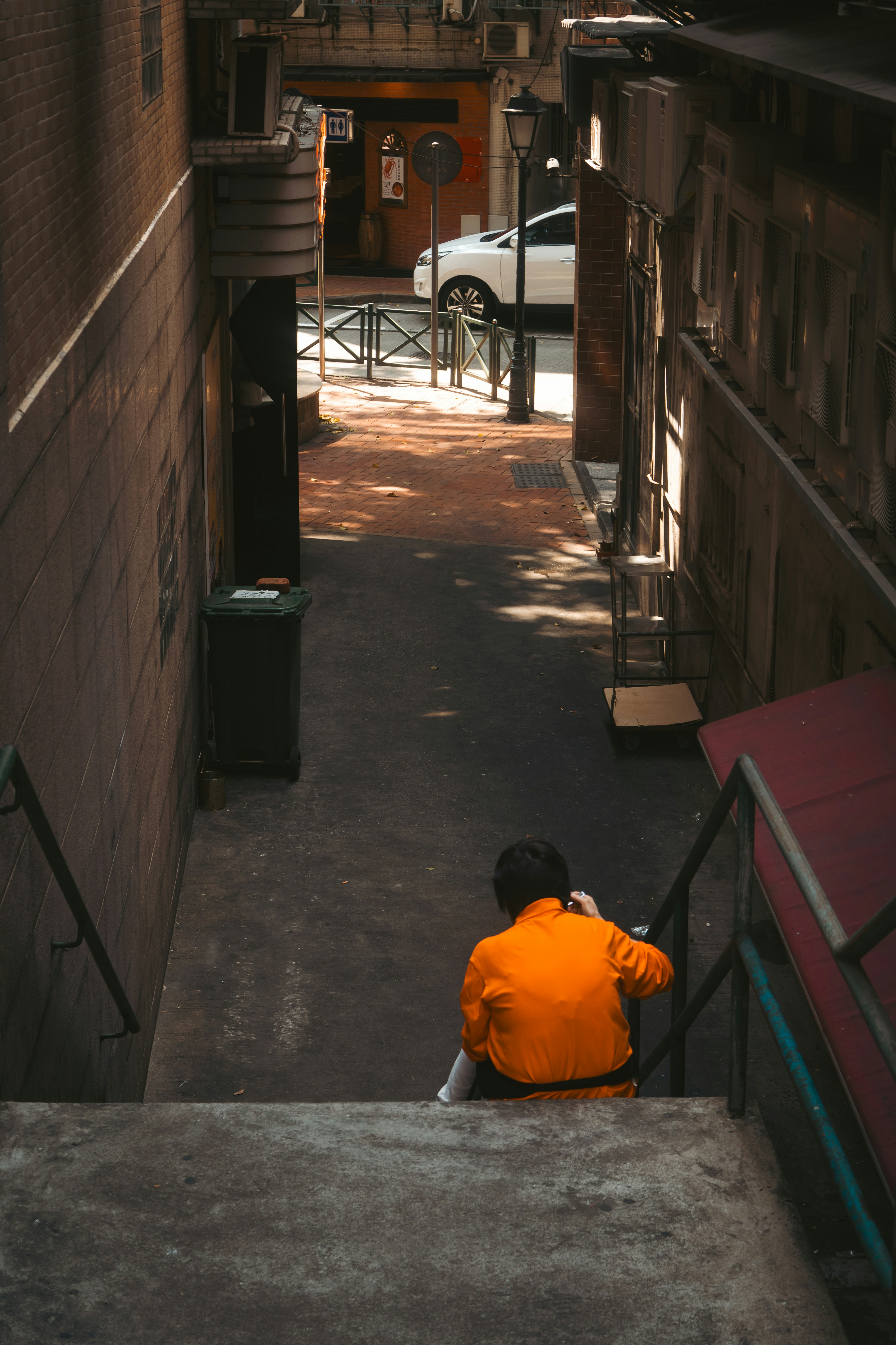 Staircase in Shadow: A Bright Orange Moment at the Alley’s Edge