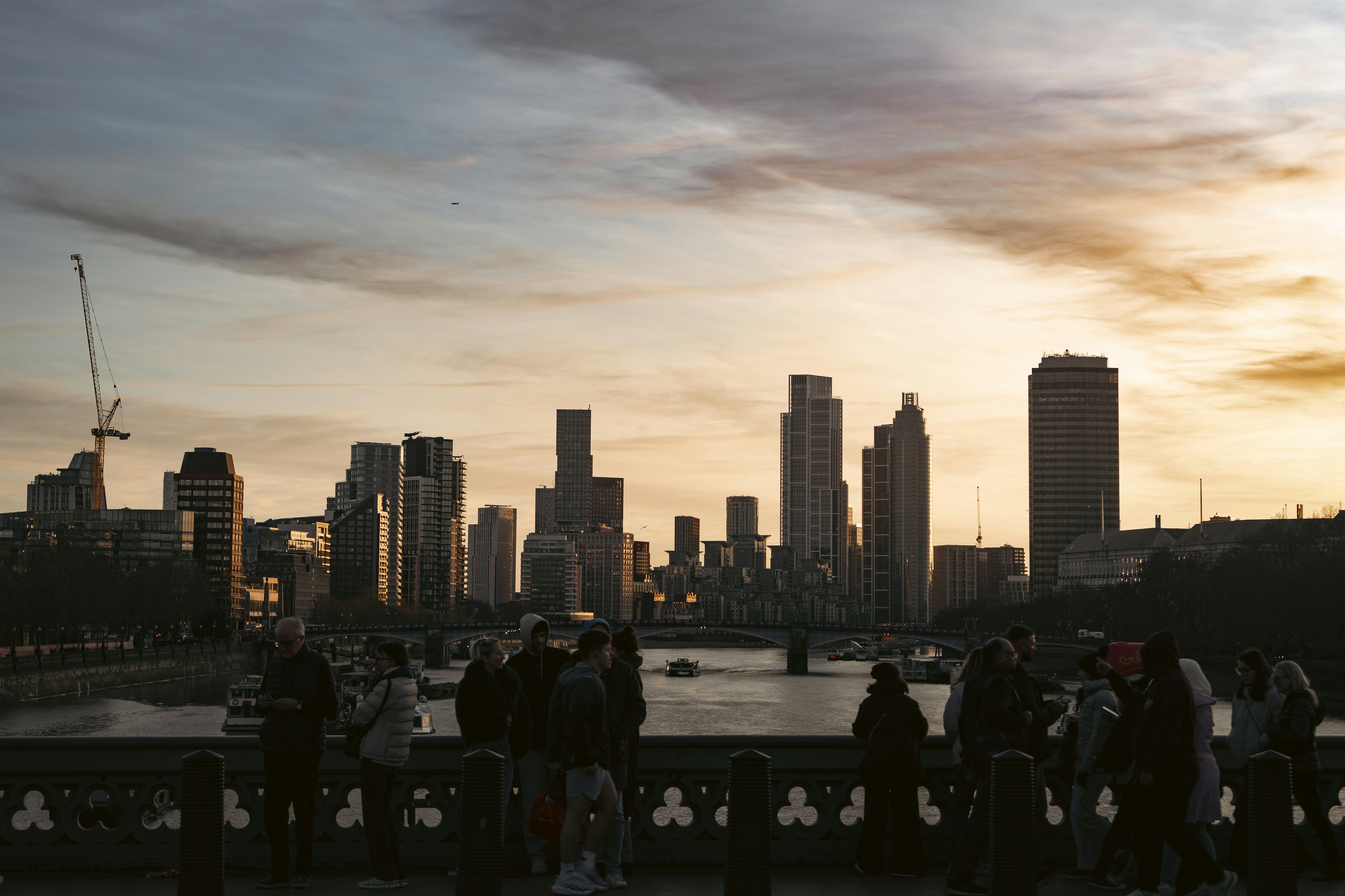 City Silhouette at Dusk: People along the Riverfront Beneath a Quiet Skyline