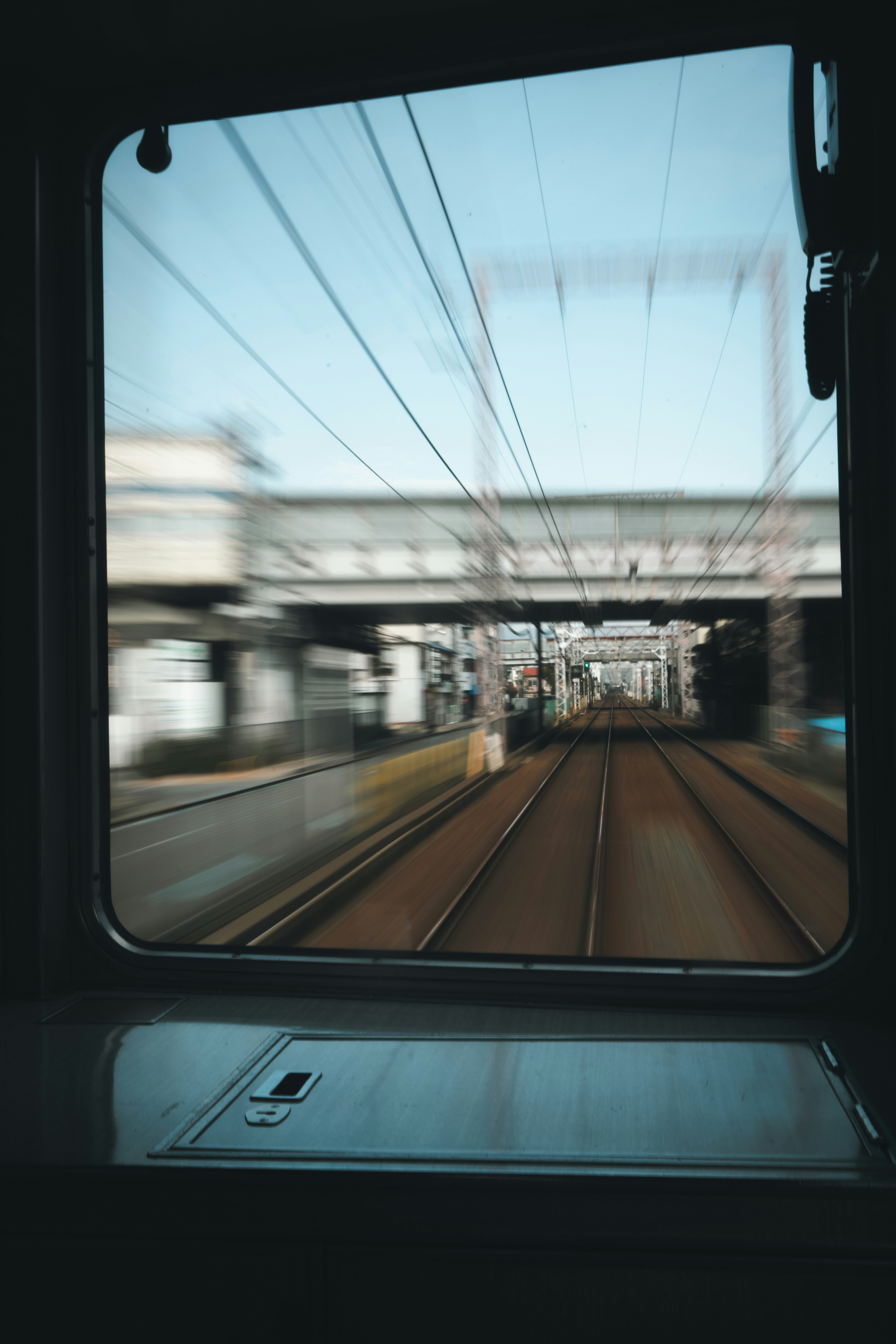 Through the Moving Glass: Rails Stretching Into the City