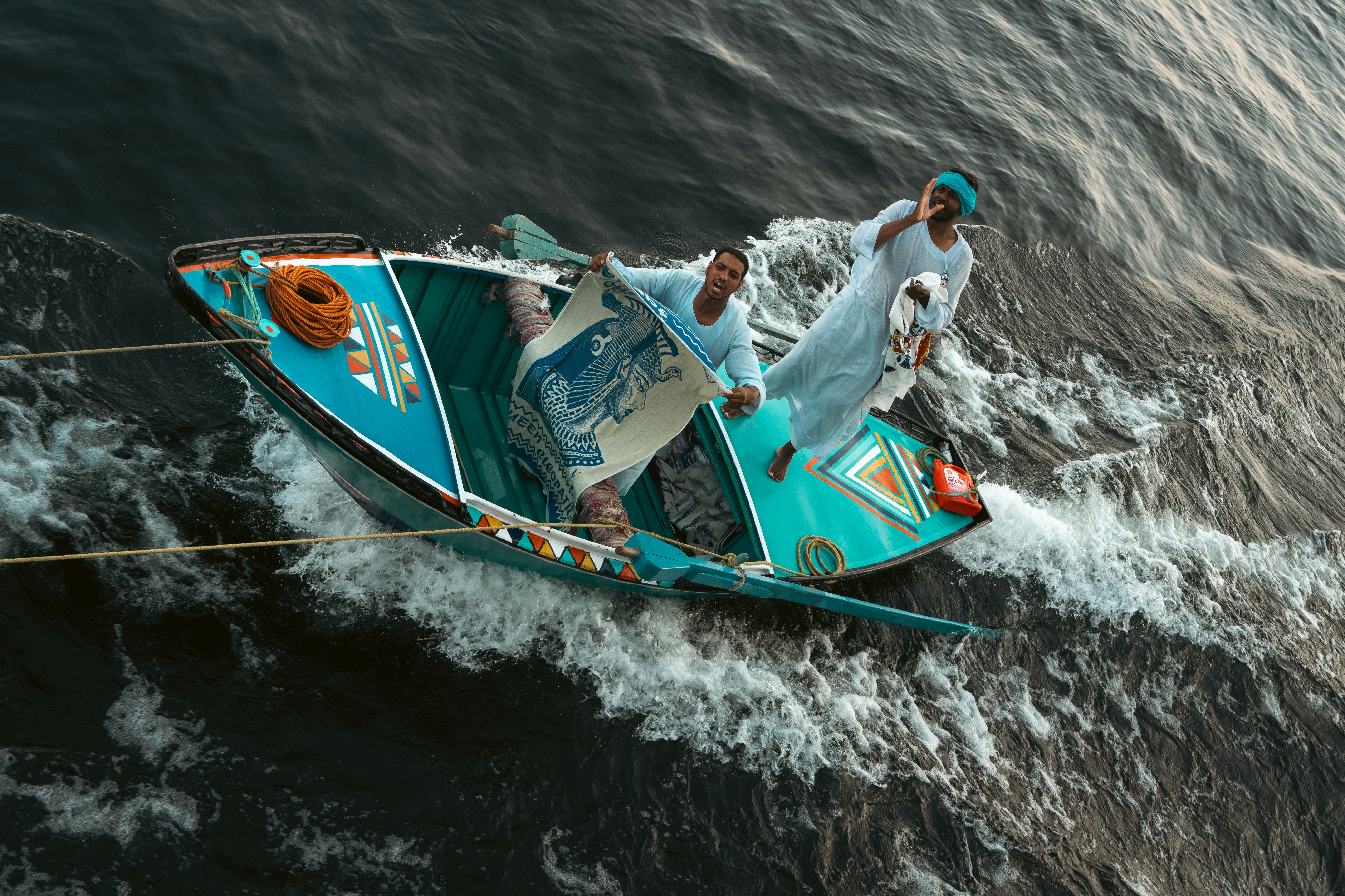 Surfing the Sea: a turquoise boat braves the waves with the crew mid-action