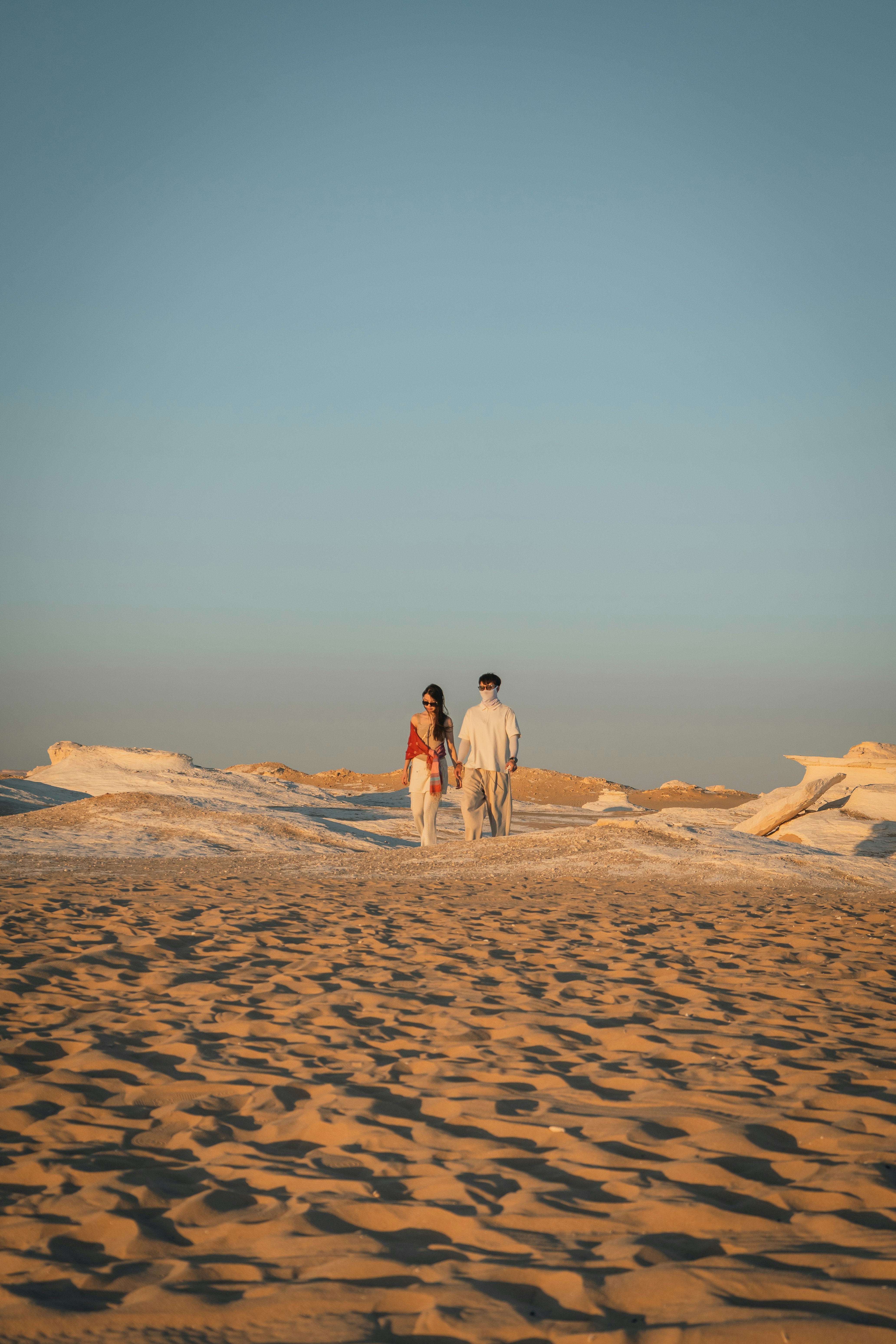 Couple walking in a desert landscape at sunset