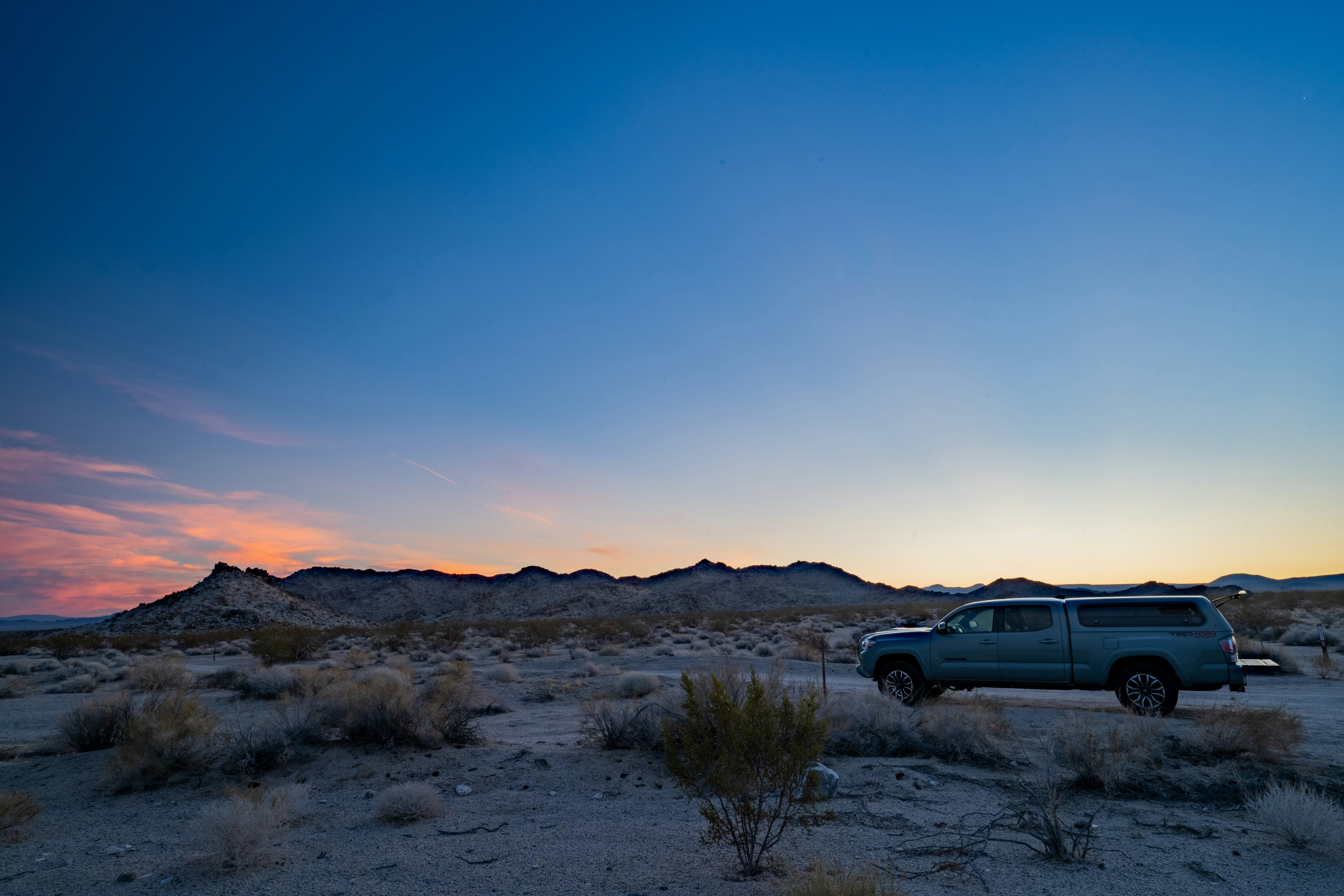Desert Sunset Roadtrip: A Lone SUV at Distant Hills