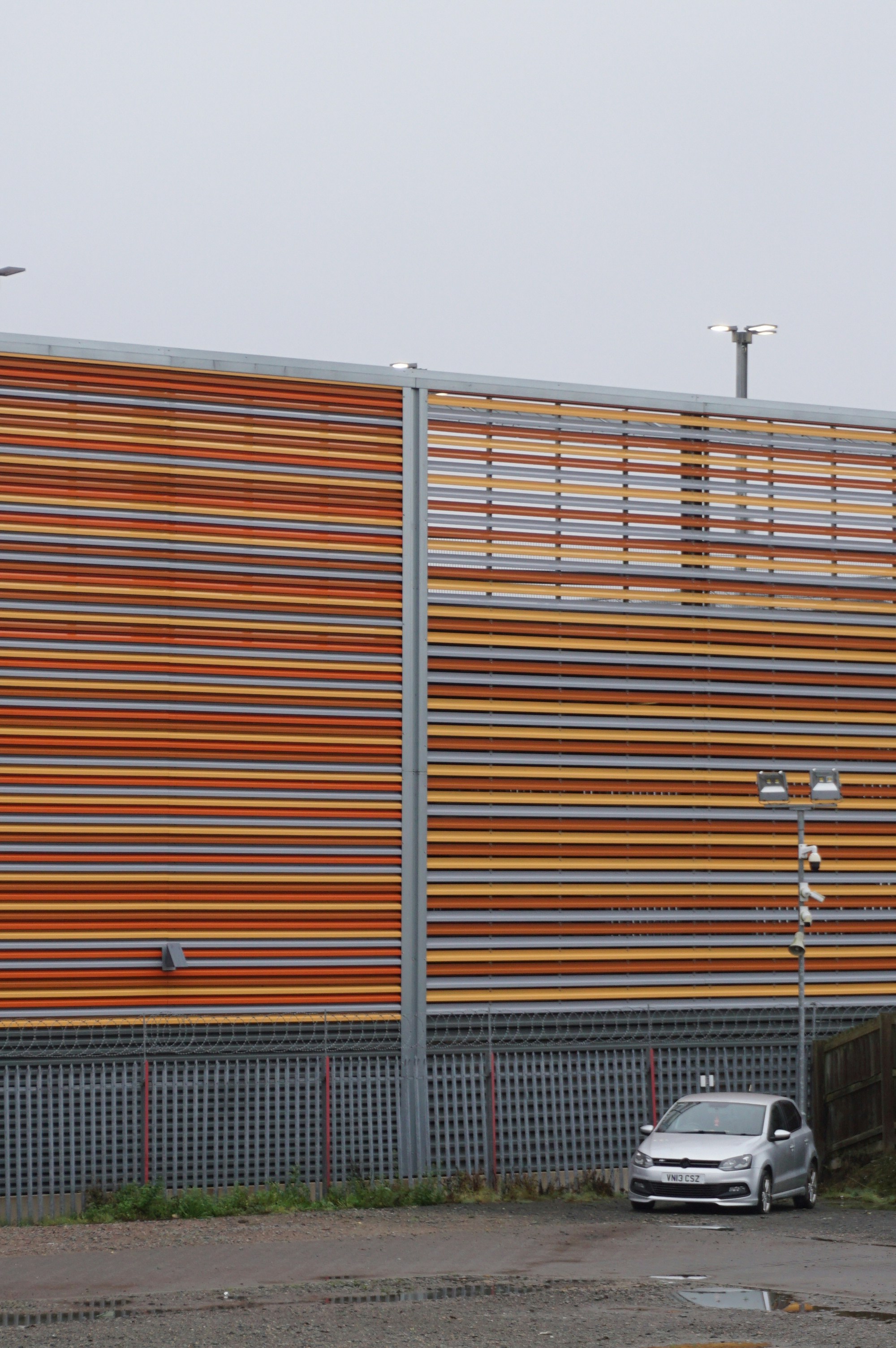 Industrial Silence: A Silver Car at the Foot of Striped Facades