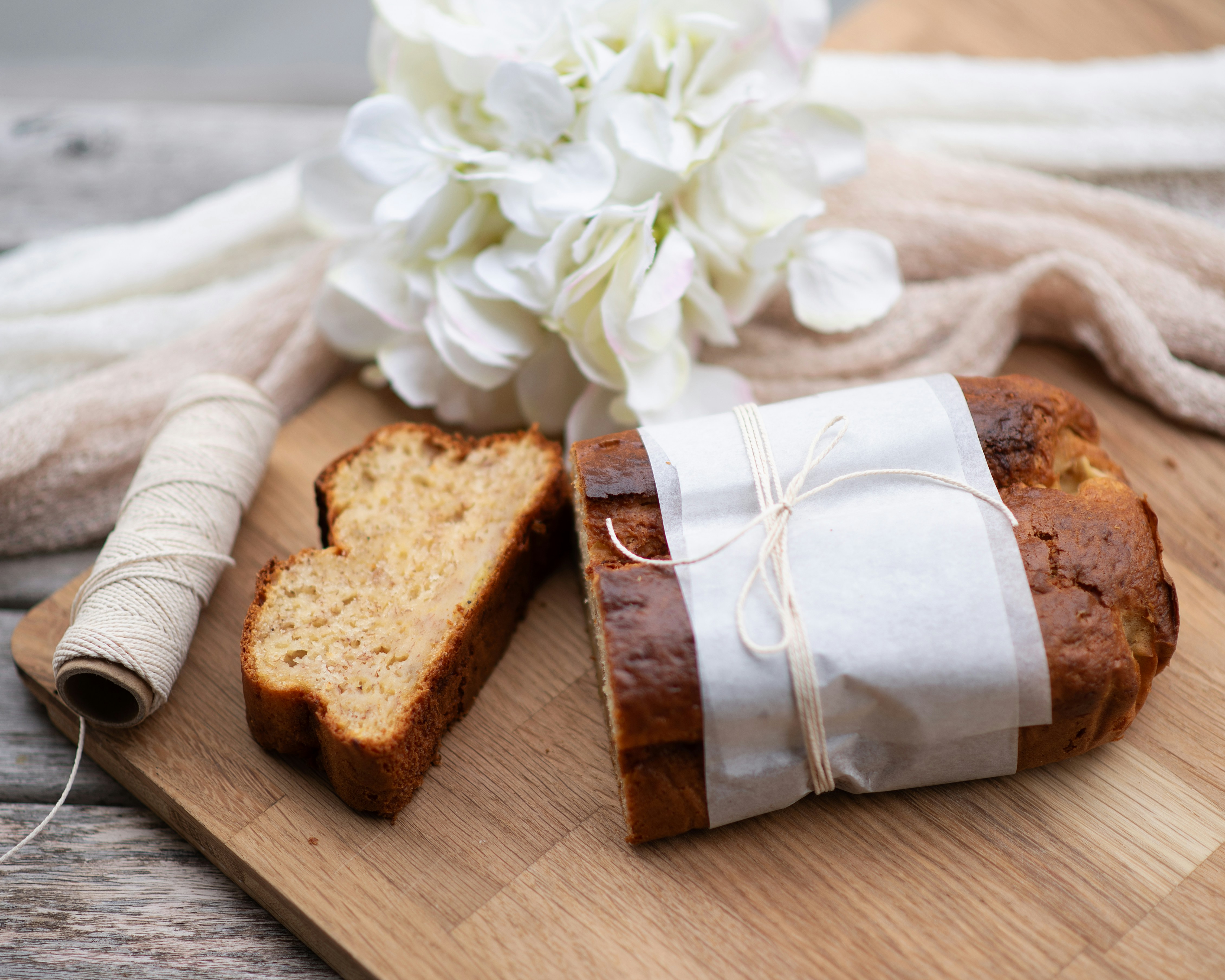 Sun-kissed loaf on a wooden board with white blossoms