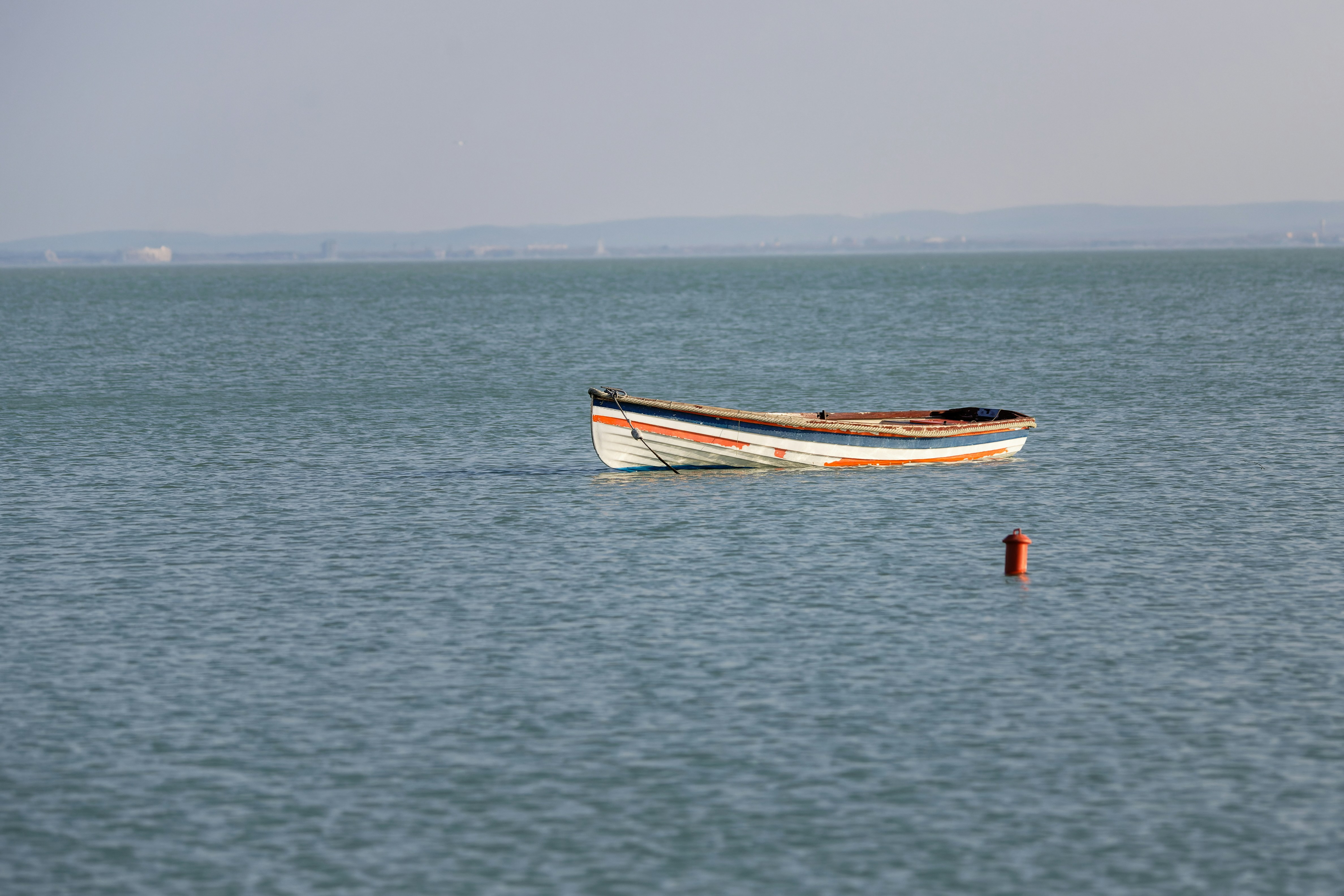 Solitary Boat on a Calm Sea under a Quiet Horizon