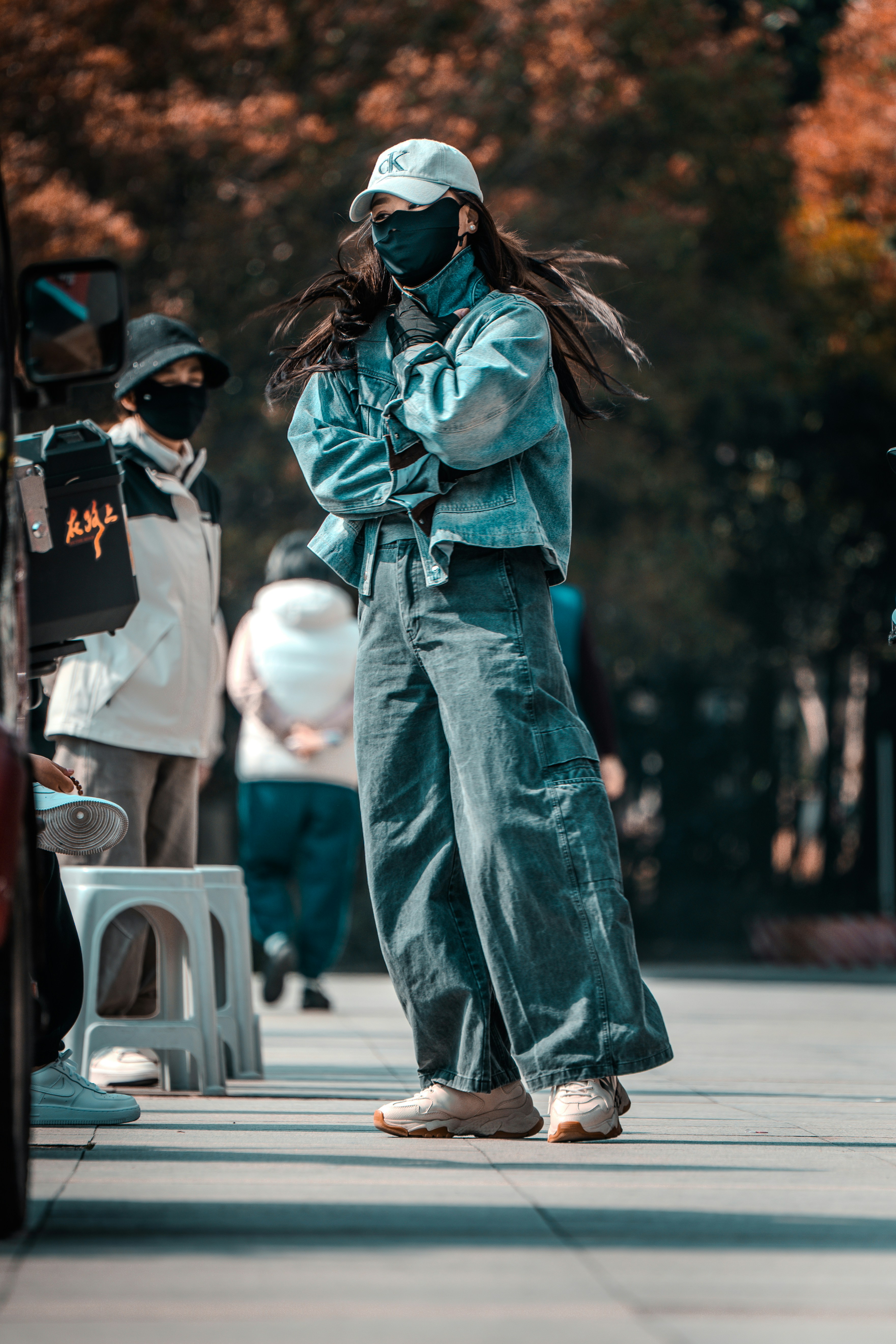 Masked dancer in denim: a street-side moment under autumn light
