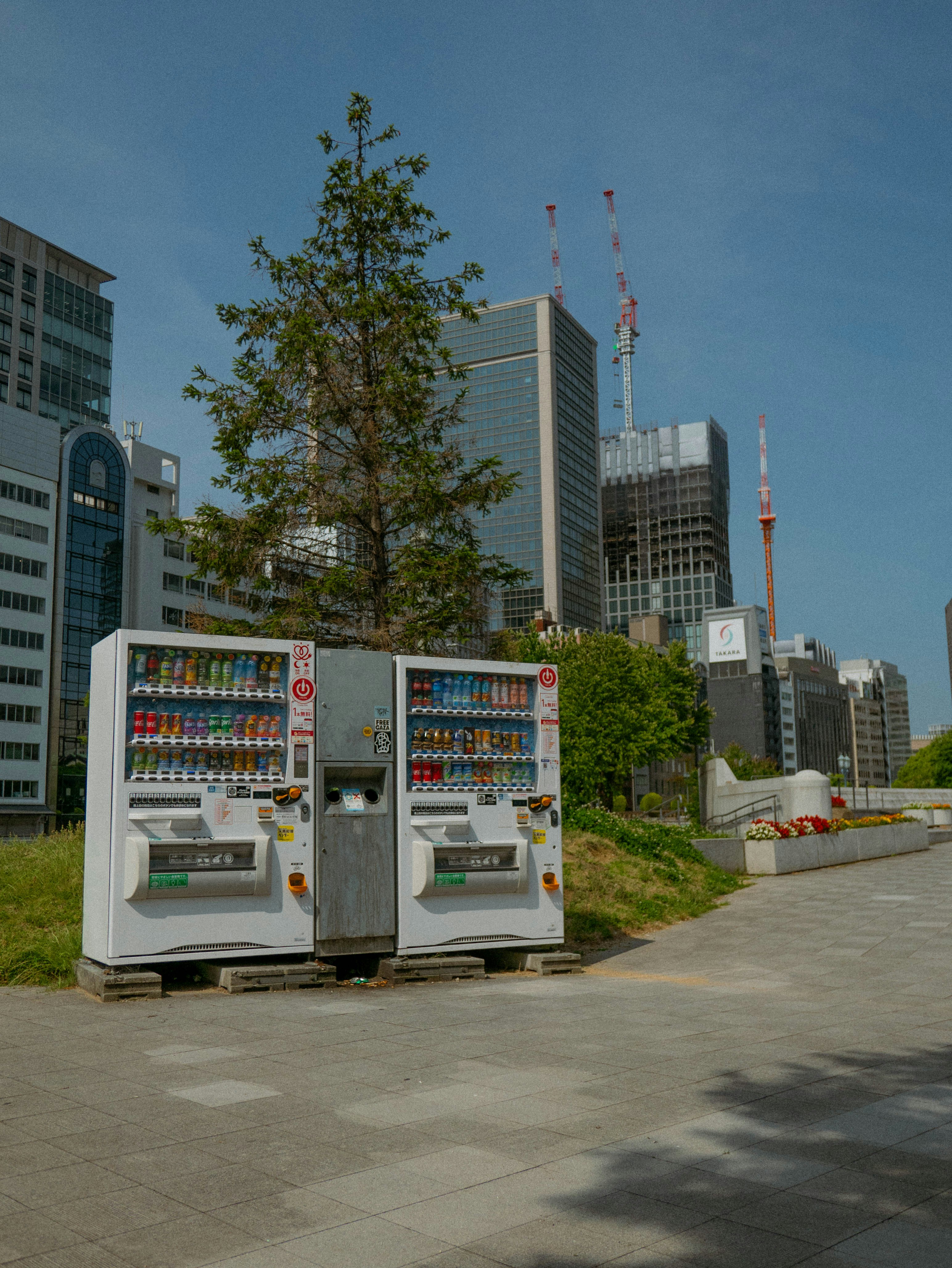 Two vending machines stand in front of city buildings.