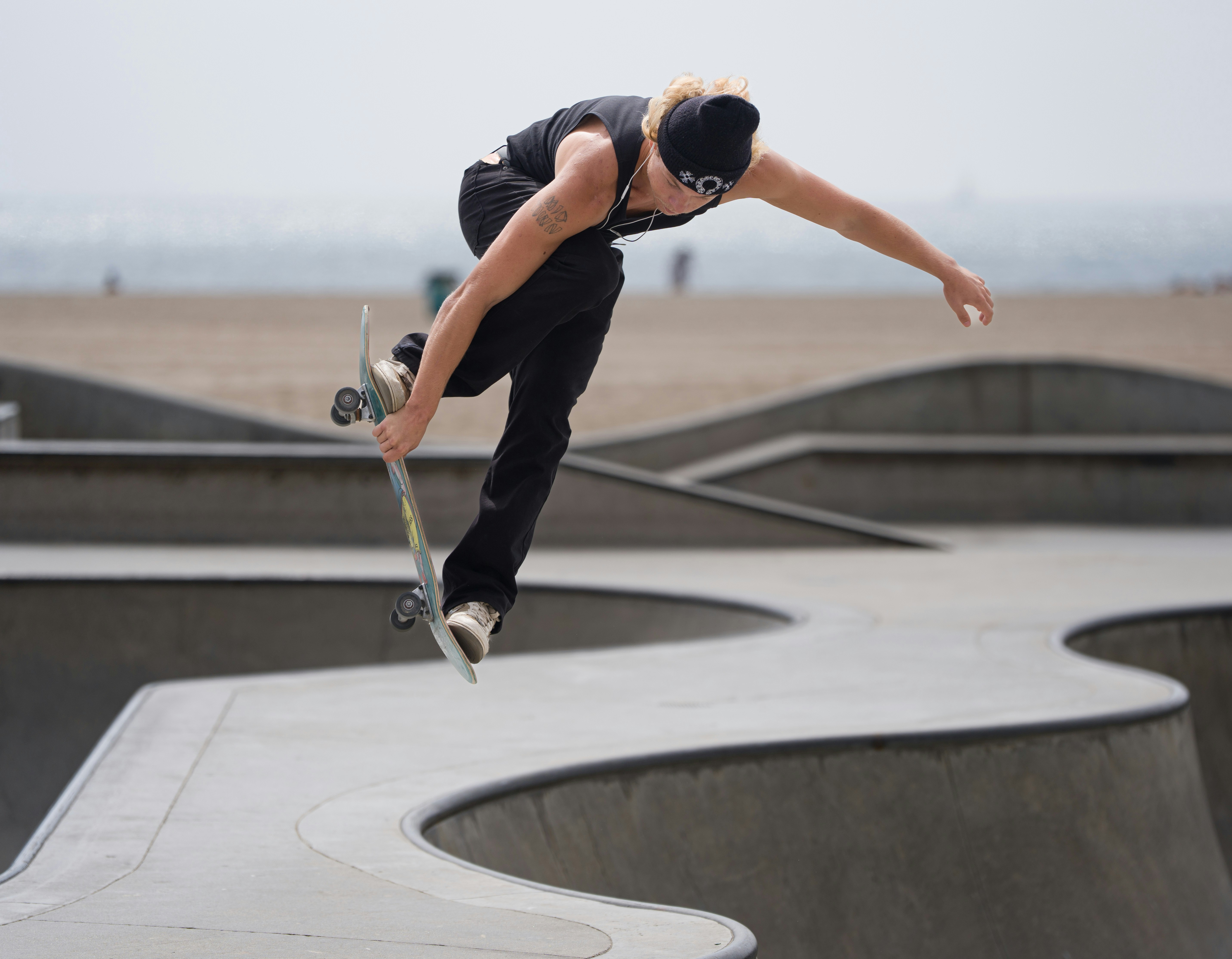 Airborne Grind: Skateboarder Silhouette Above Concrete Waves