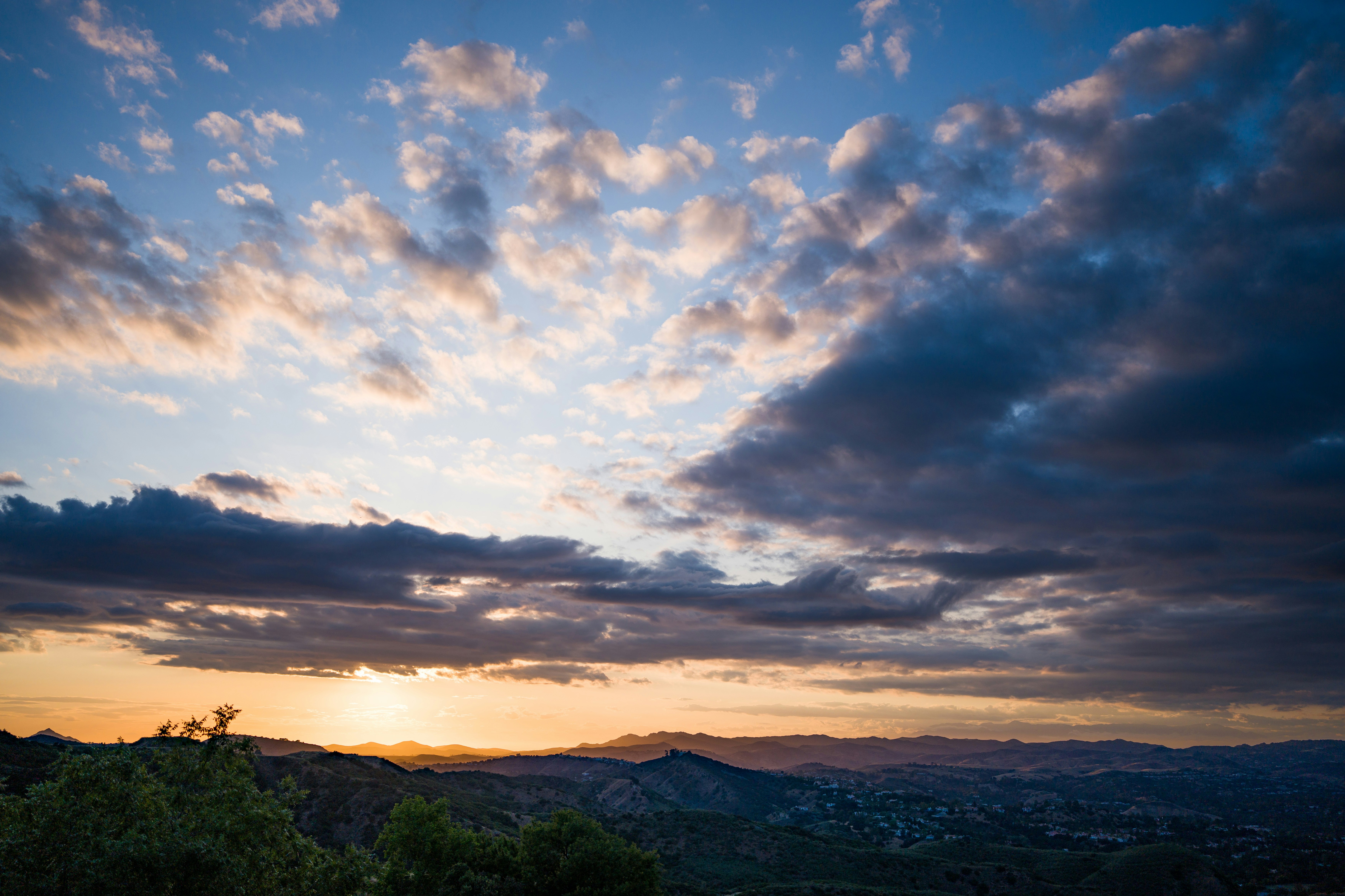 Sunset Over Rolling Hills: A Quiet Dusk Beneath Expansive Clouds