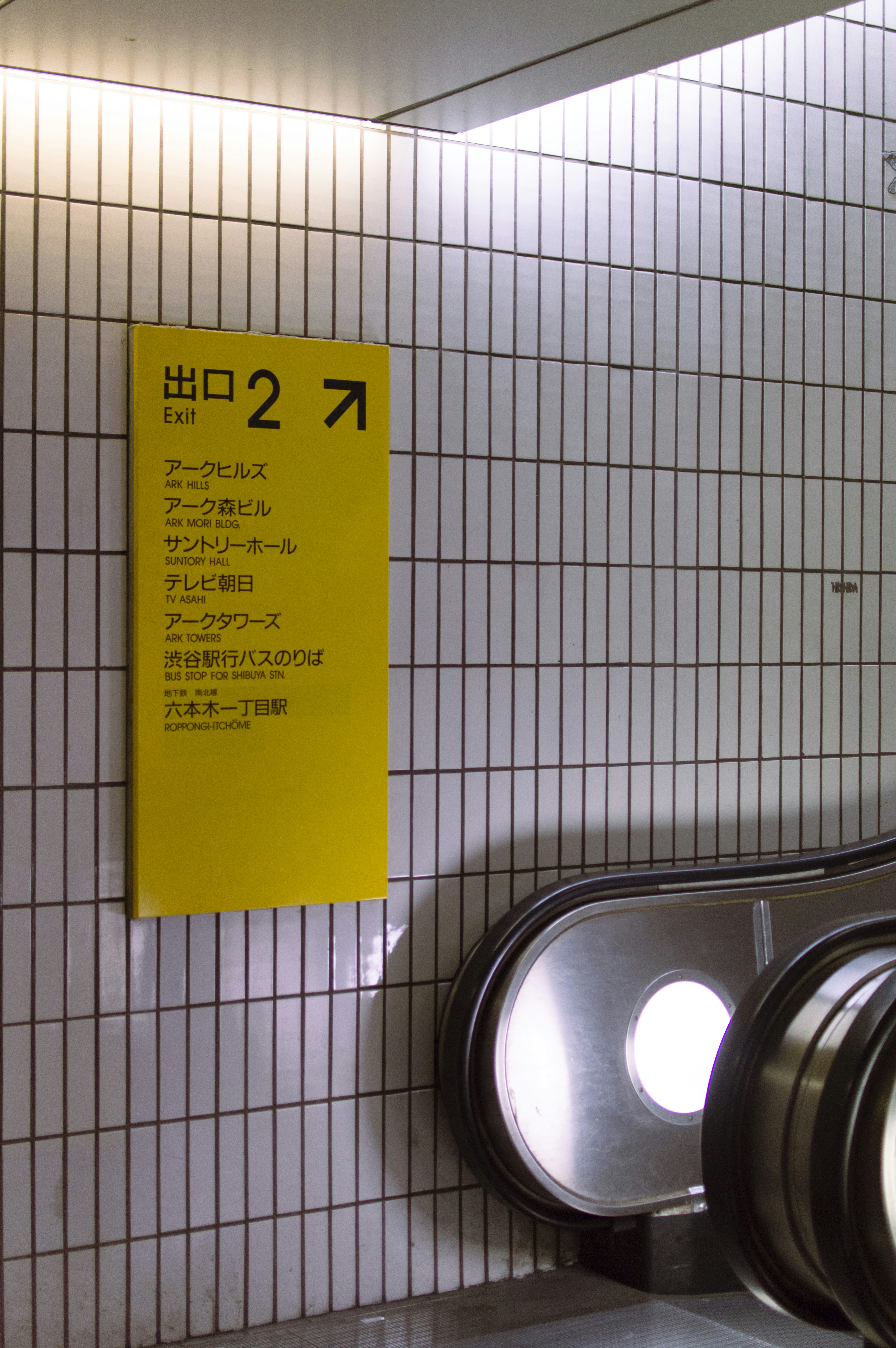 Yellow Sign at the Subway Exit: A Neon-White Tile Corridor