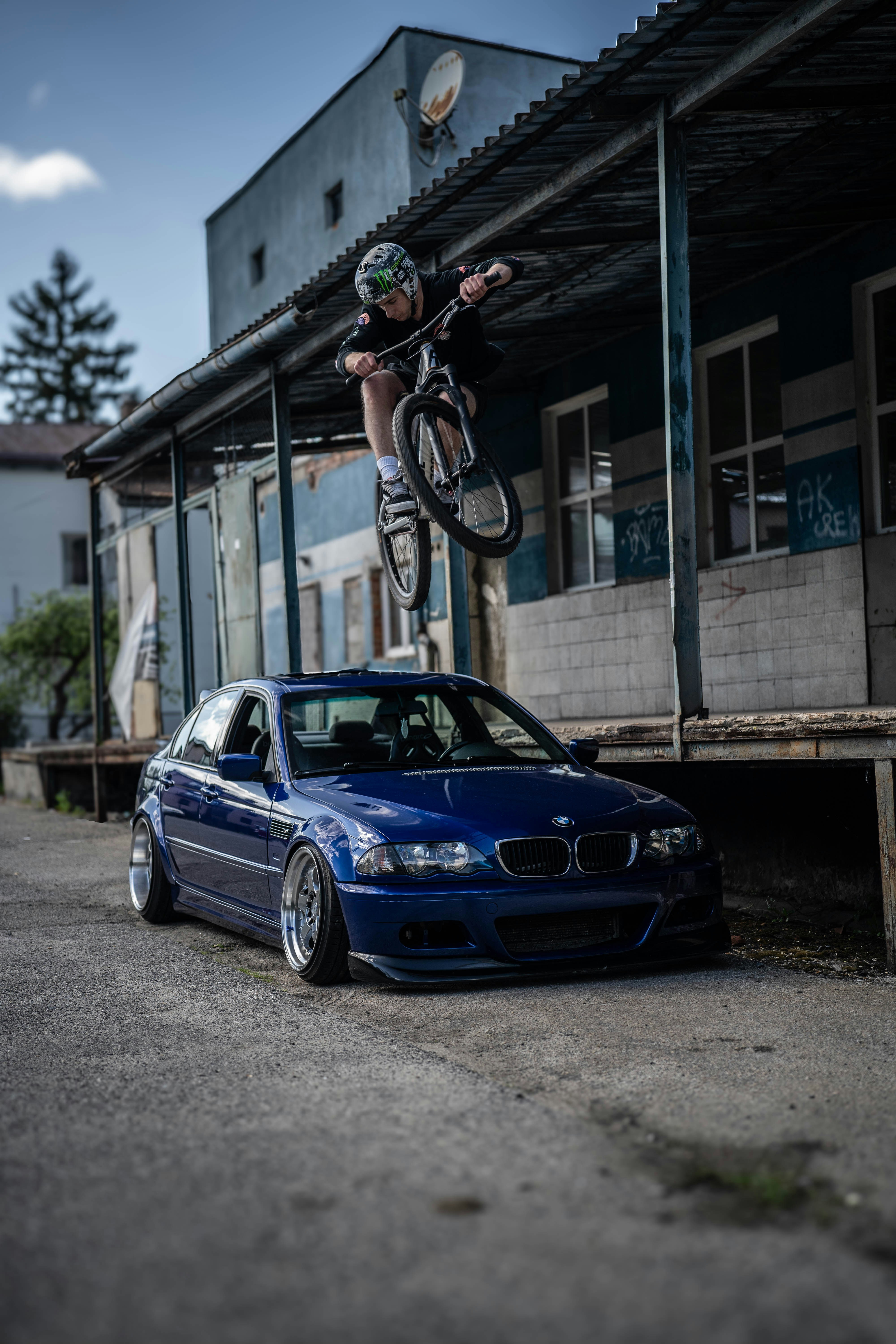 Midair Maverick: BMX Rider Clears the Warehouse Ramps Over a Blue Sedan