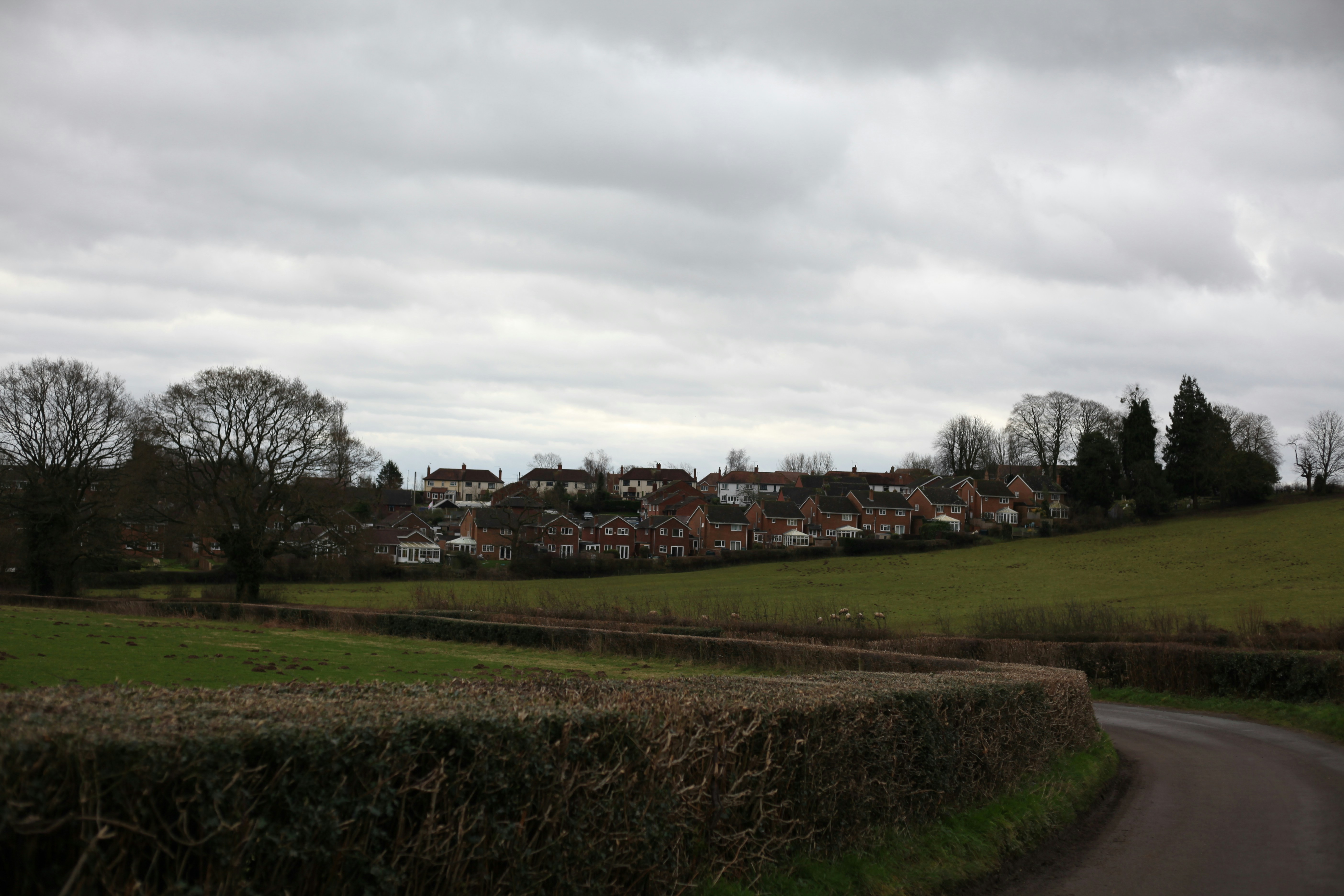 Rural village tucked along a winding lane under a brooding sky