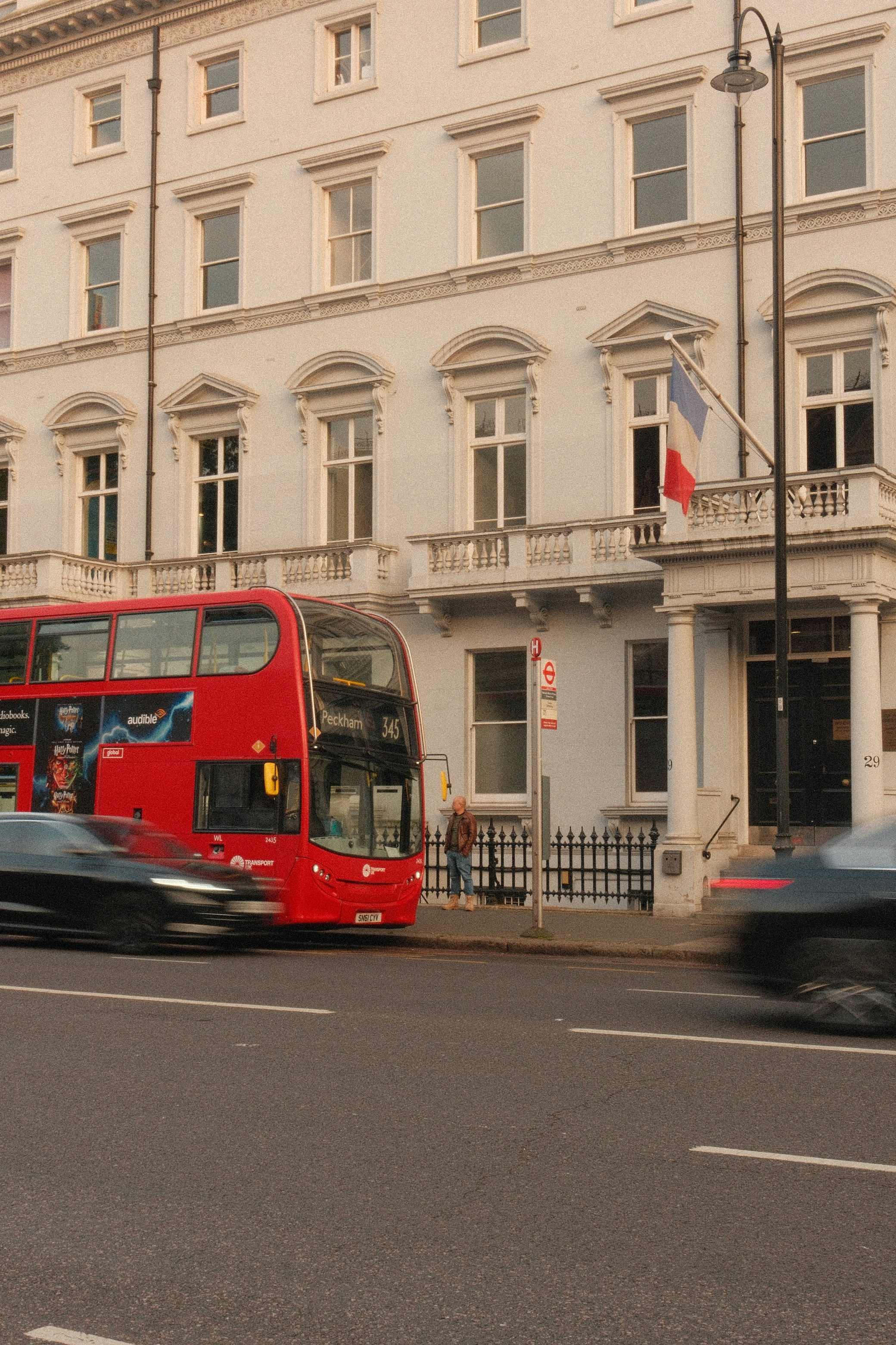 London Street Pulse: Red Double-Decker at Dusk Behind Classical Facade