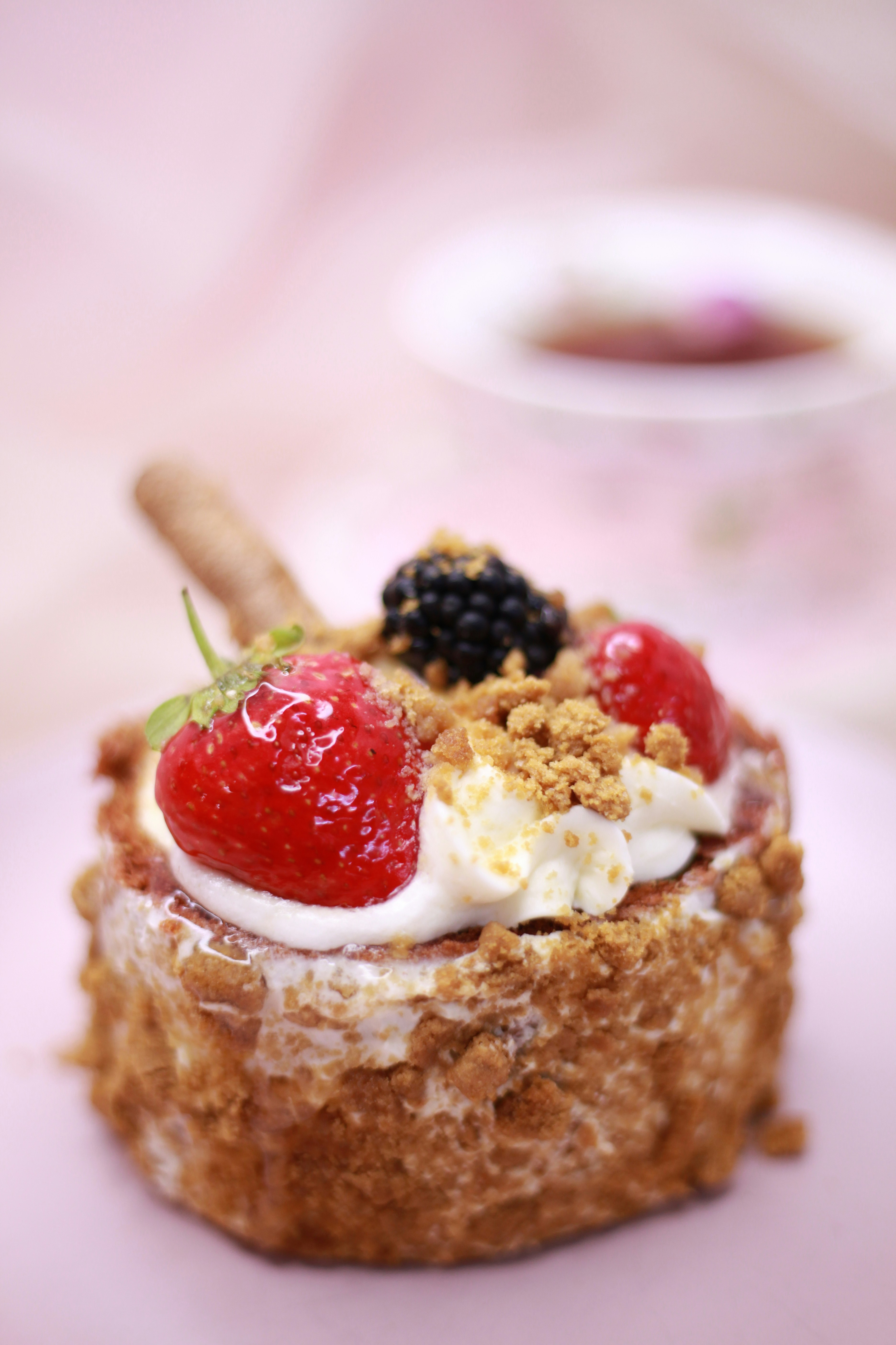 Crumbled Cream Cheese Tartlet with Berries on a Soft Pink Surface